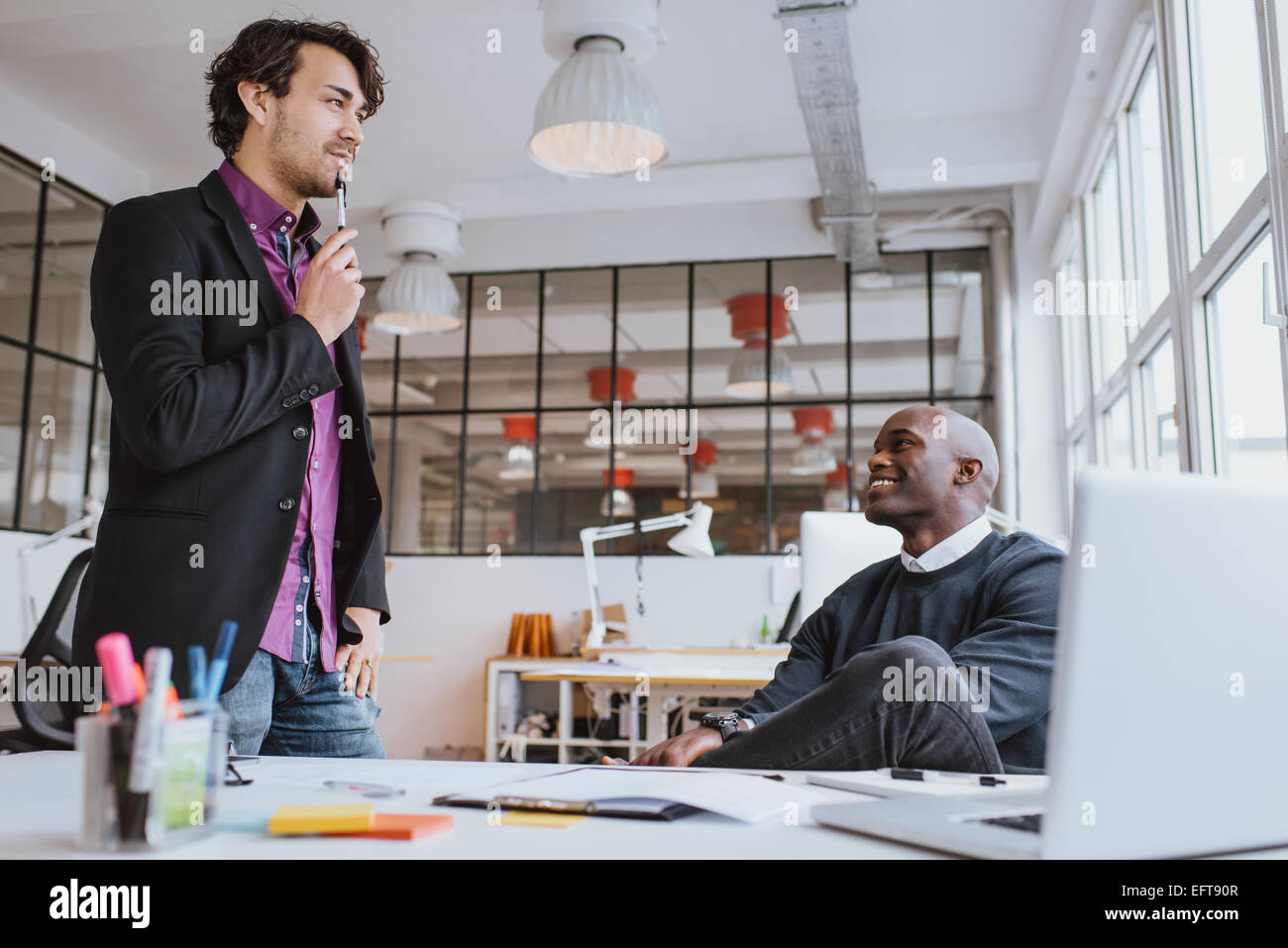 Two young office workers discussing work in office. Office manager with ...