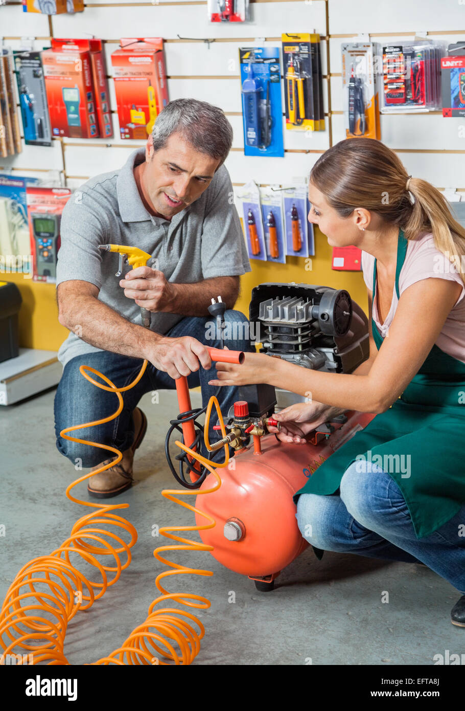 Saleswoman Showing Air Compressor To Customer In Store Stock Photo - Alamy