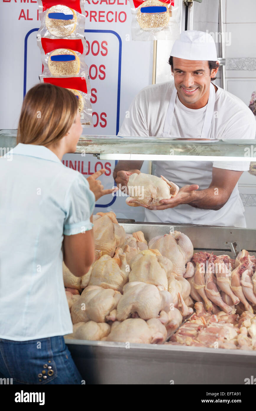 Butcher Showing Fresh Chicken Meat To Customer Stock Photo - Alamy