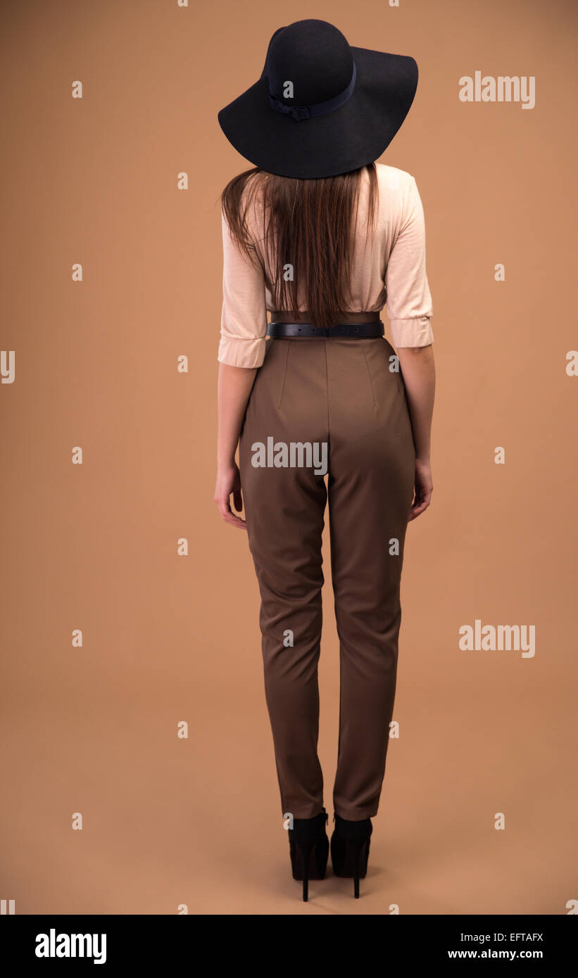 Back view portrait of a fashion woman standing over brown background ...