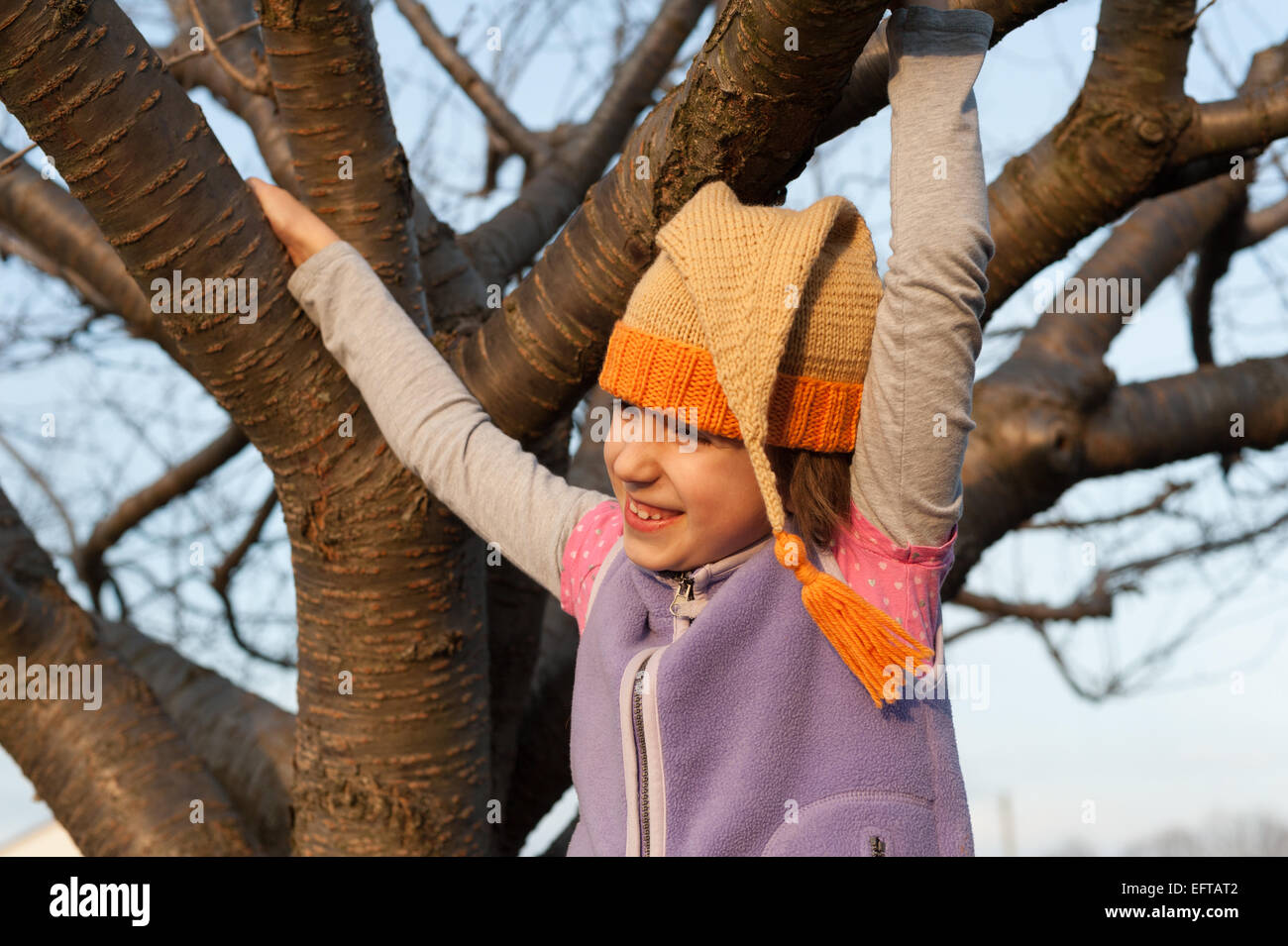 Young girl swinging on a tree branch in the autumn wearing knitted ...
