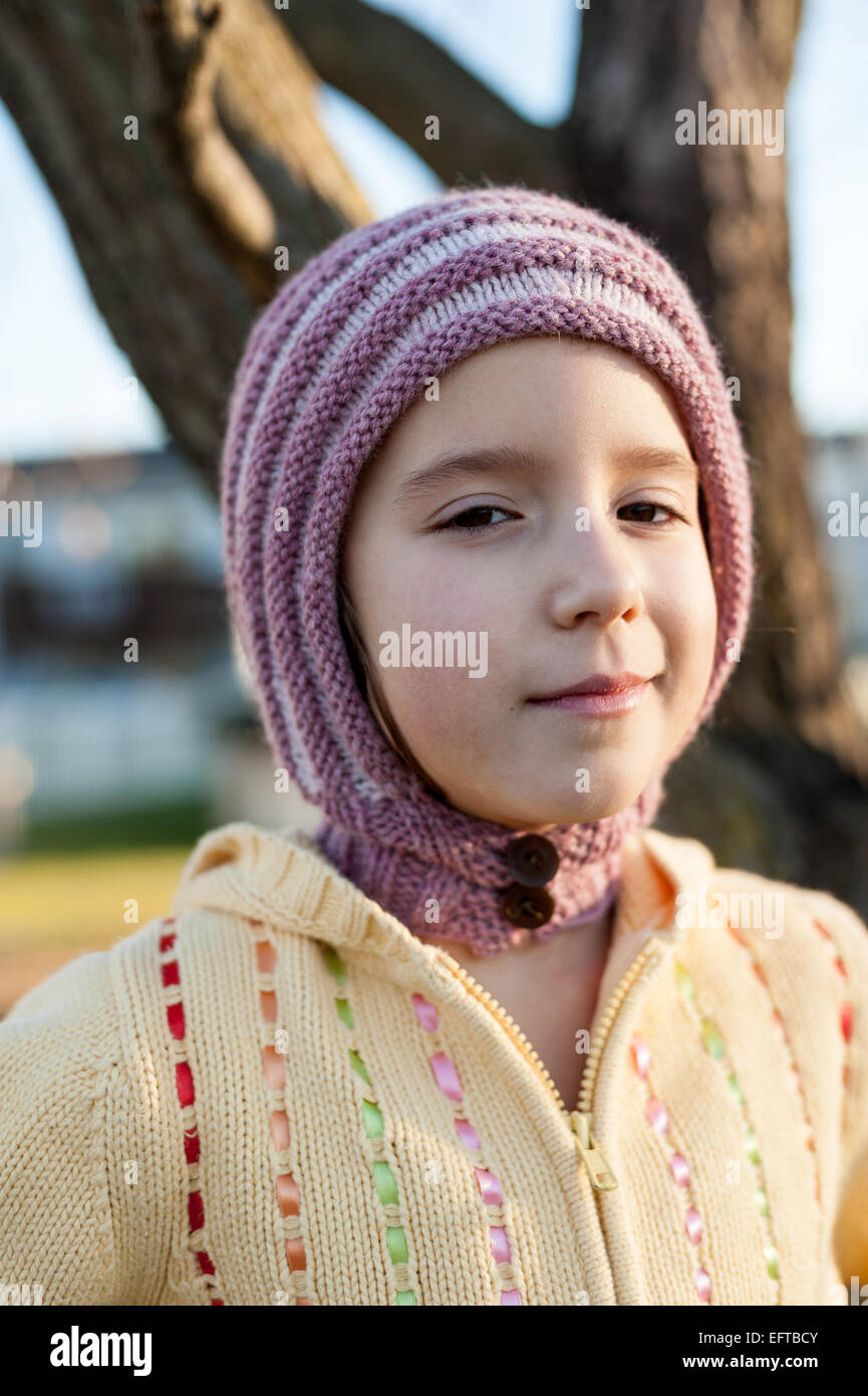 Young girl with a curious smile wearing a knit hat and sweater Stock ...