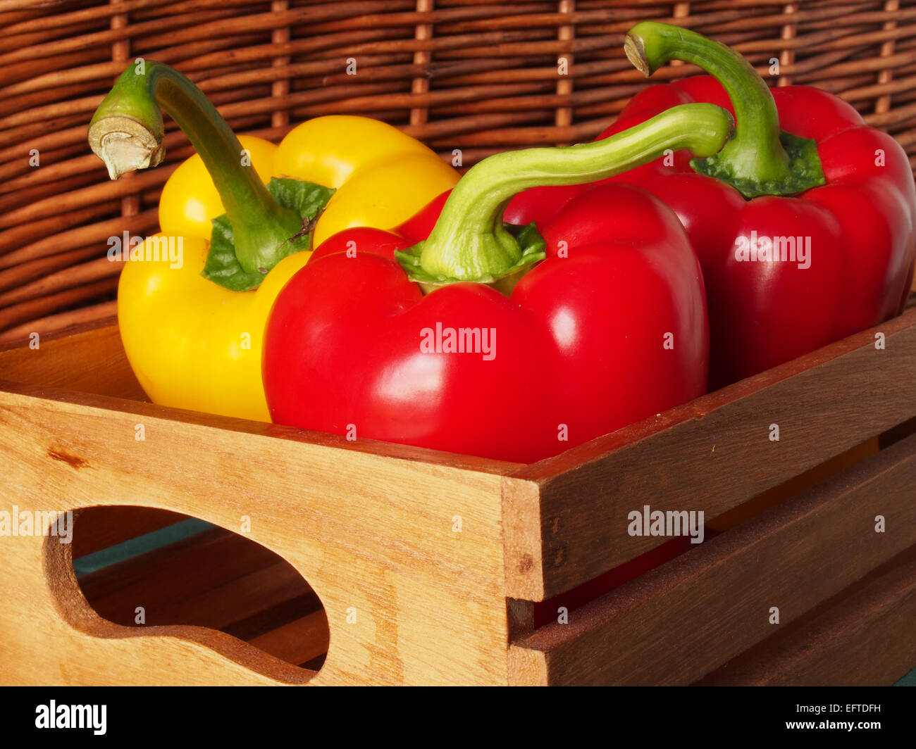 Red and yellow peppers grouped together in a wooden box for storage and ...