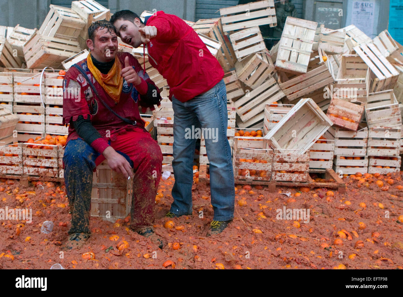 Two friends surrounded by empty crates and smashed oranges take rest ...