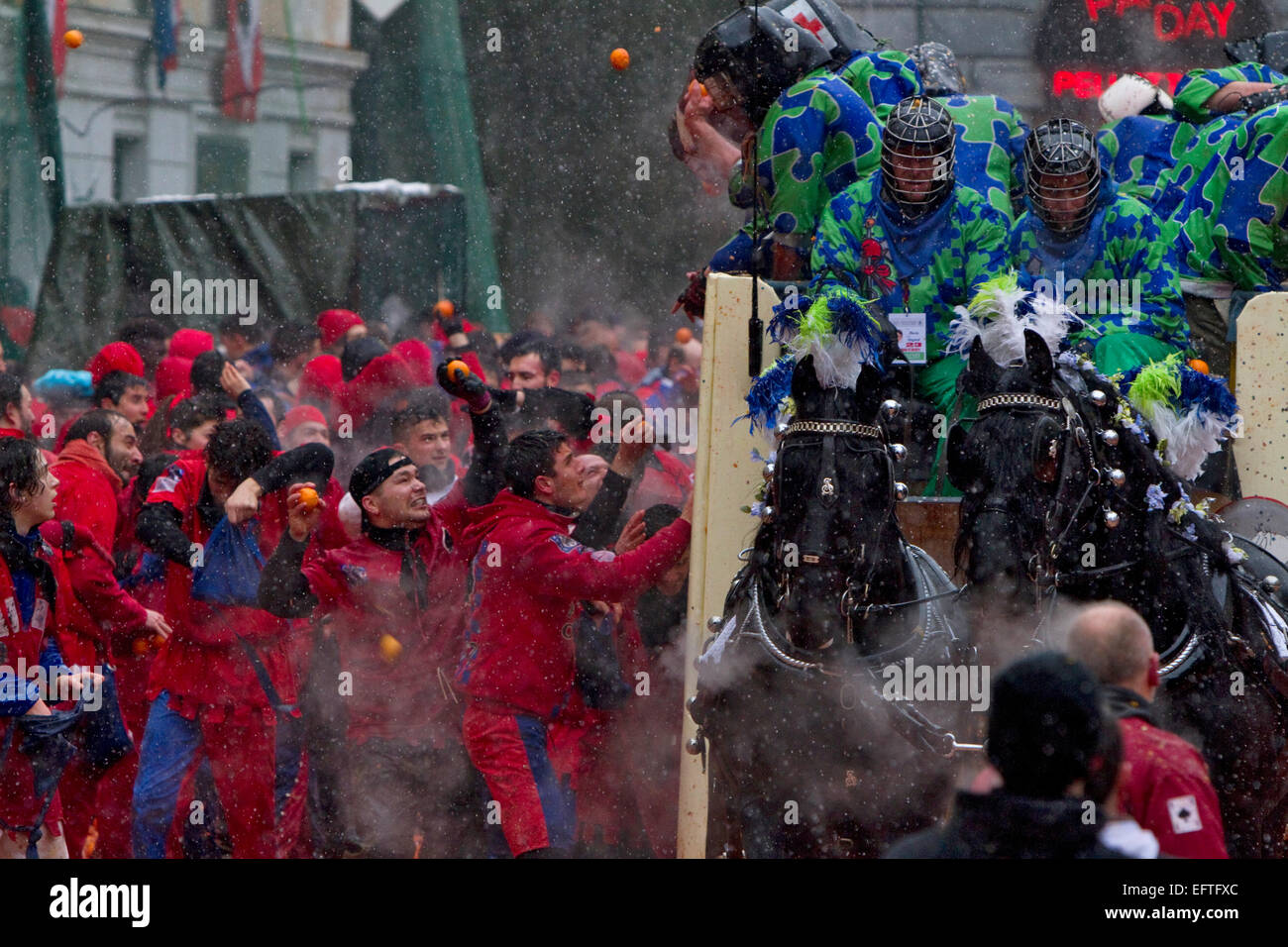 A tight crowd of orange throwers attacks a cart as part of the 'Battle ...