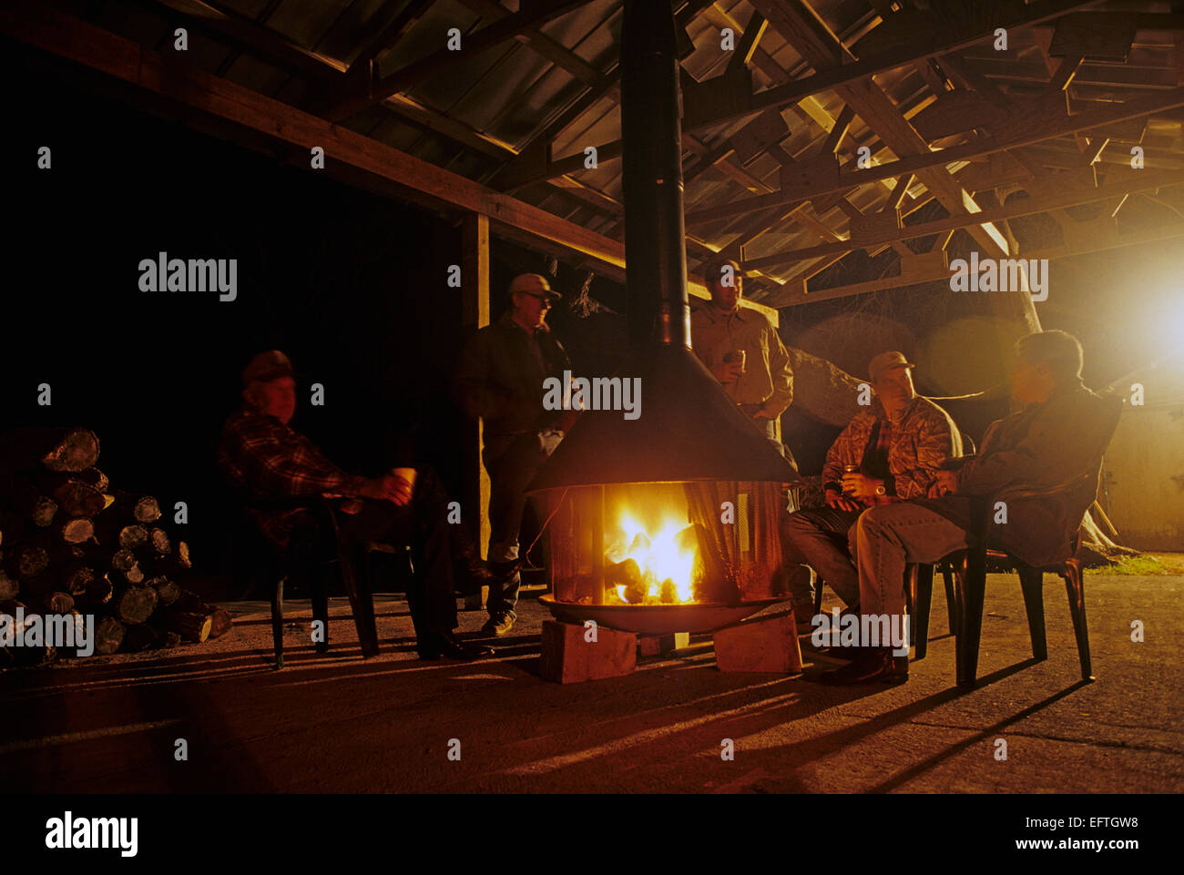 Duck hunters gathered around campfire Stock Photo - Alamy