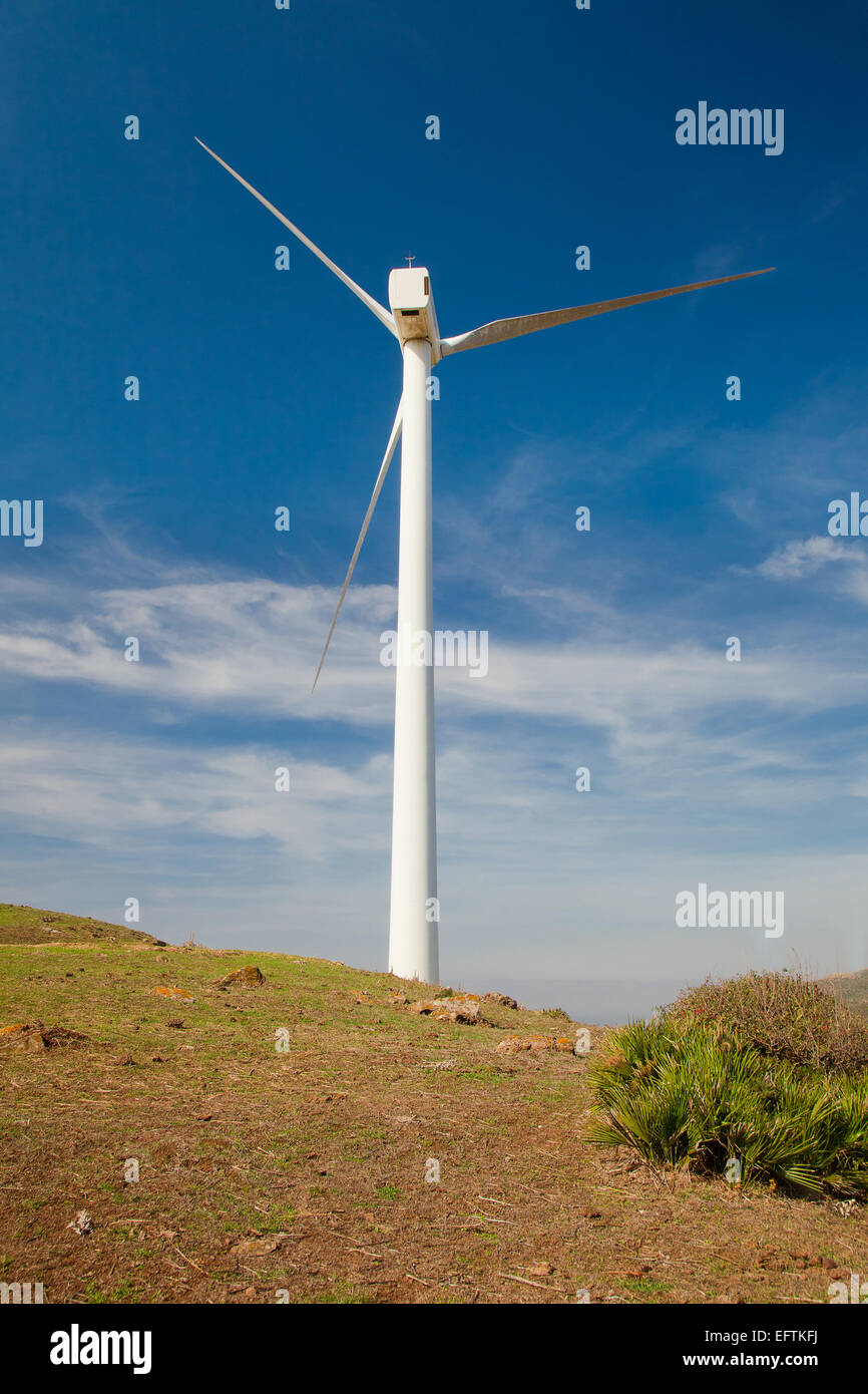 Single windmill producing electrical power on a hill against deep blue ...