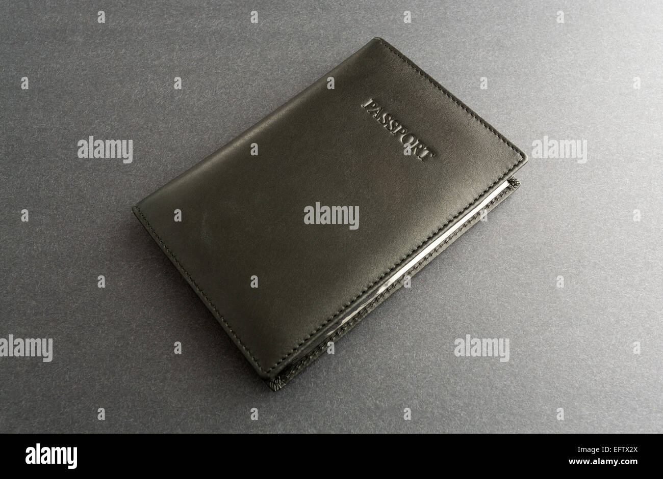 Leather passport holder with passport inside atop a dark background ...