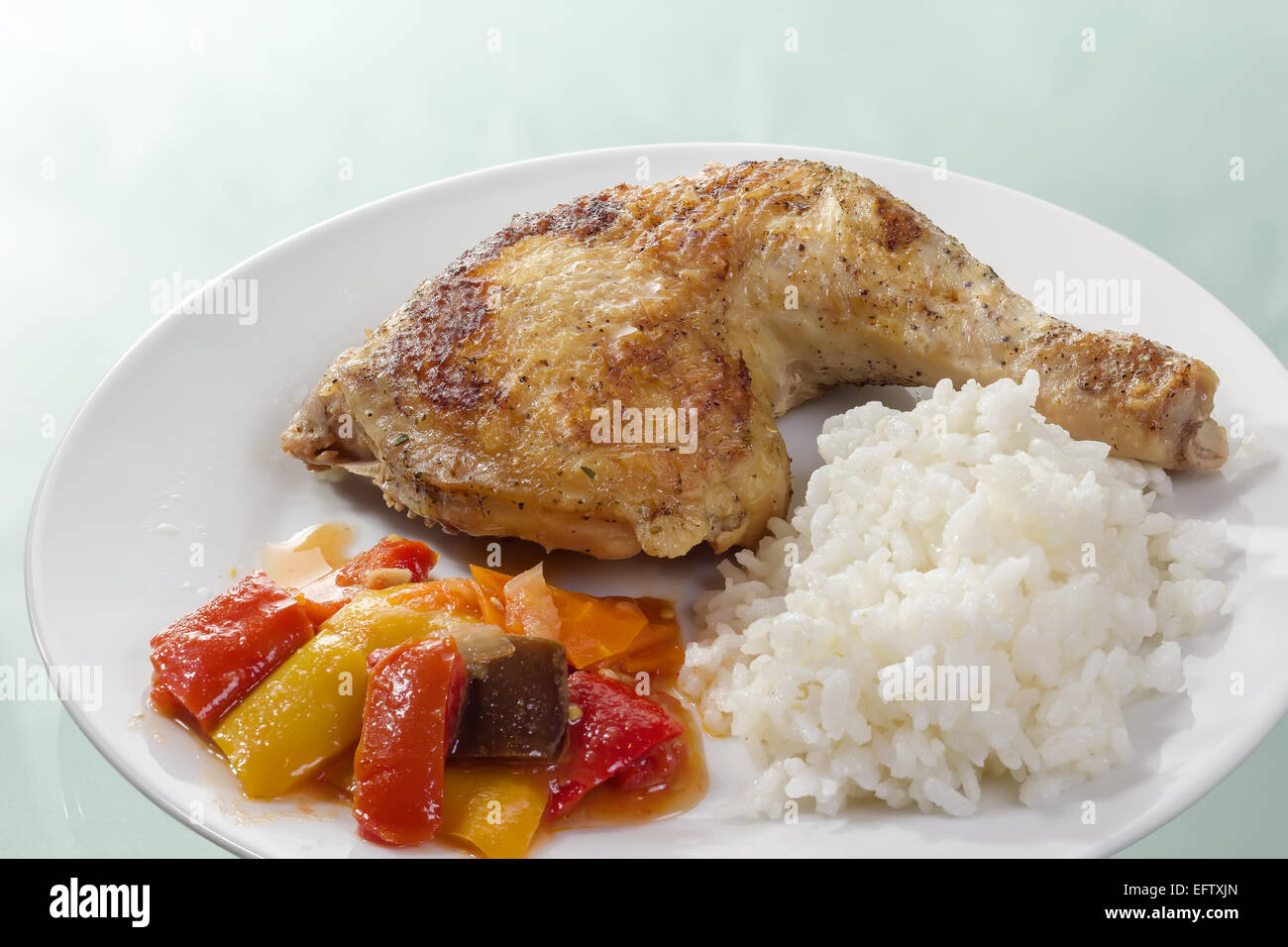 Roast chicken thigh with rice and vegetables on a white plate Stock ...