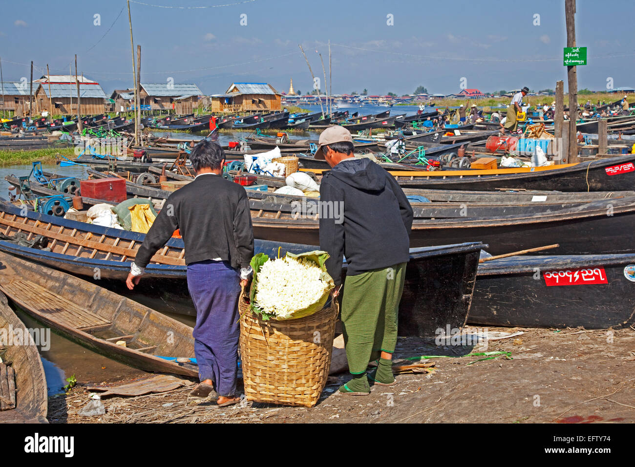 Open boats at lakeside village with traditional wooden houses on stilts ...