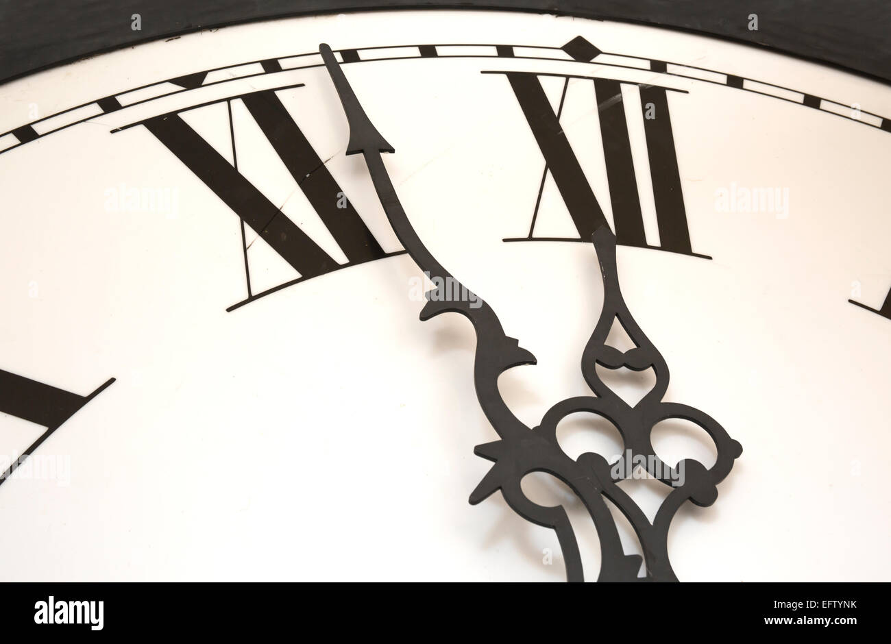Clock with black swirly hands showing almost midnight Stock Photo - Alamy