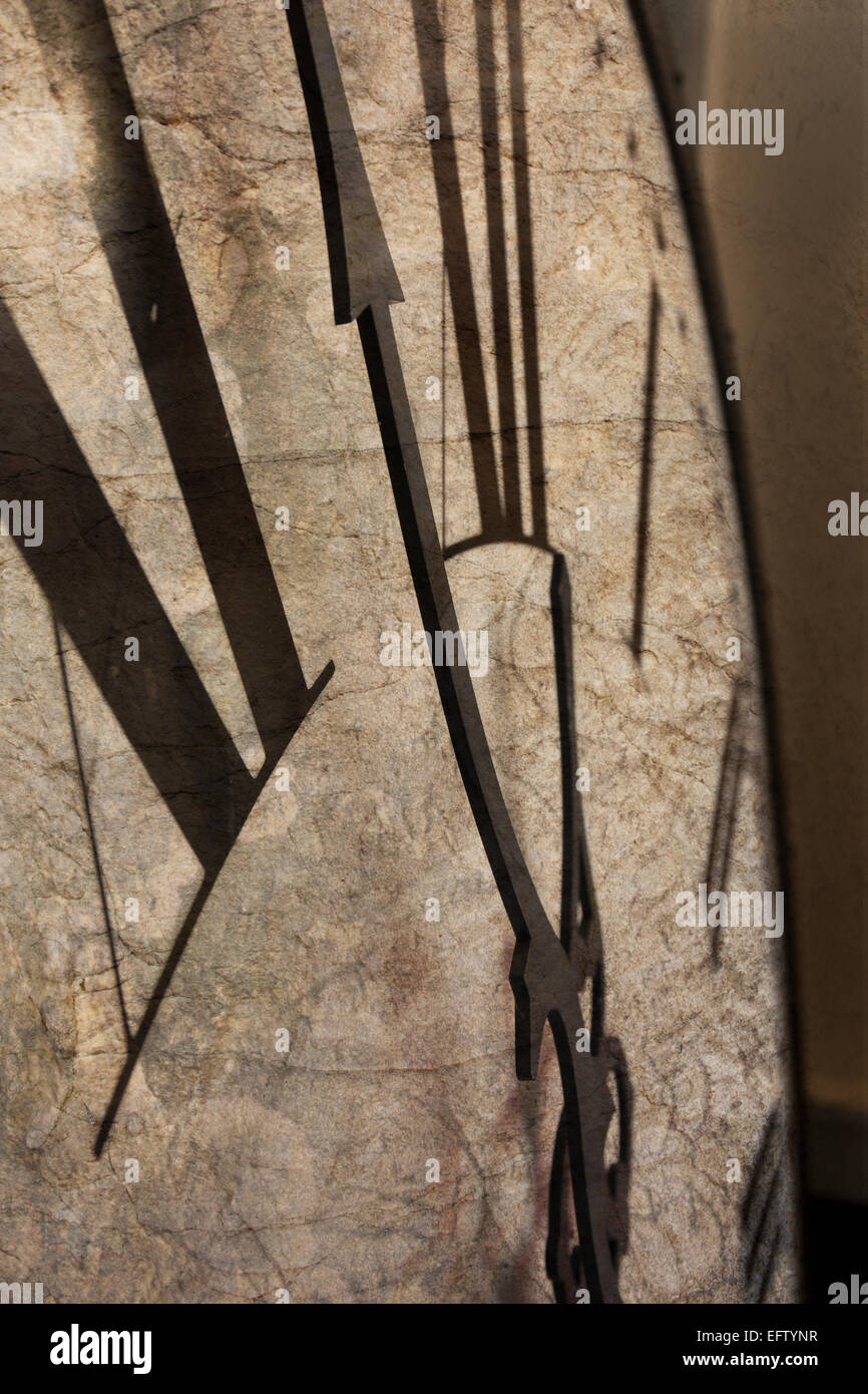 Close-up of clock with rough stone texture black hands and numbers ...