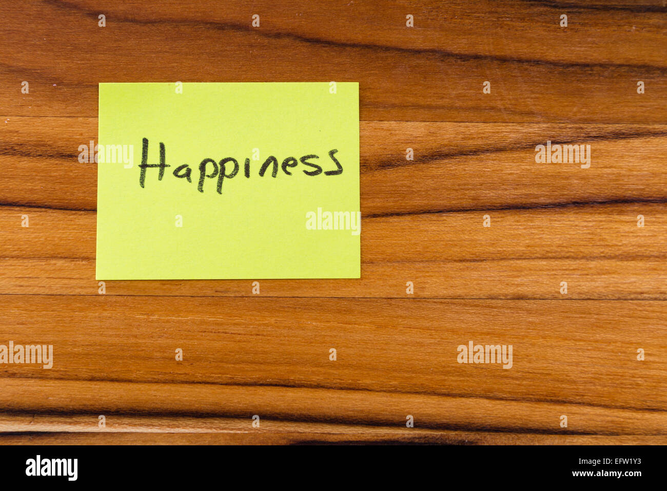 sticky note on a wooden desk with the word happiness written on it ...