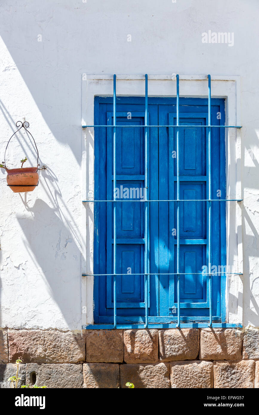 White colonial wall and old blue window with Incan stonework visible ...