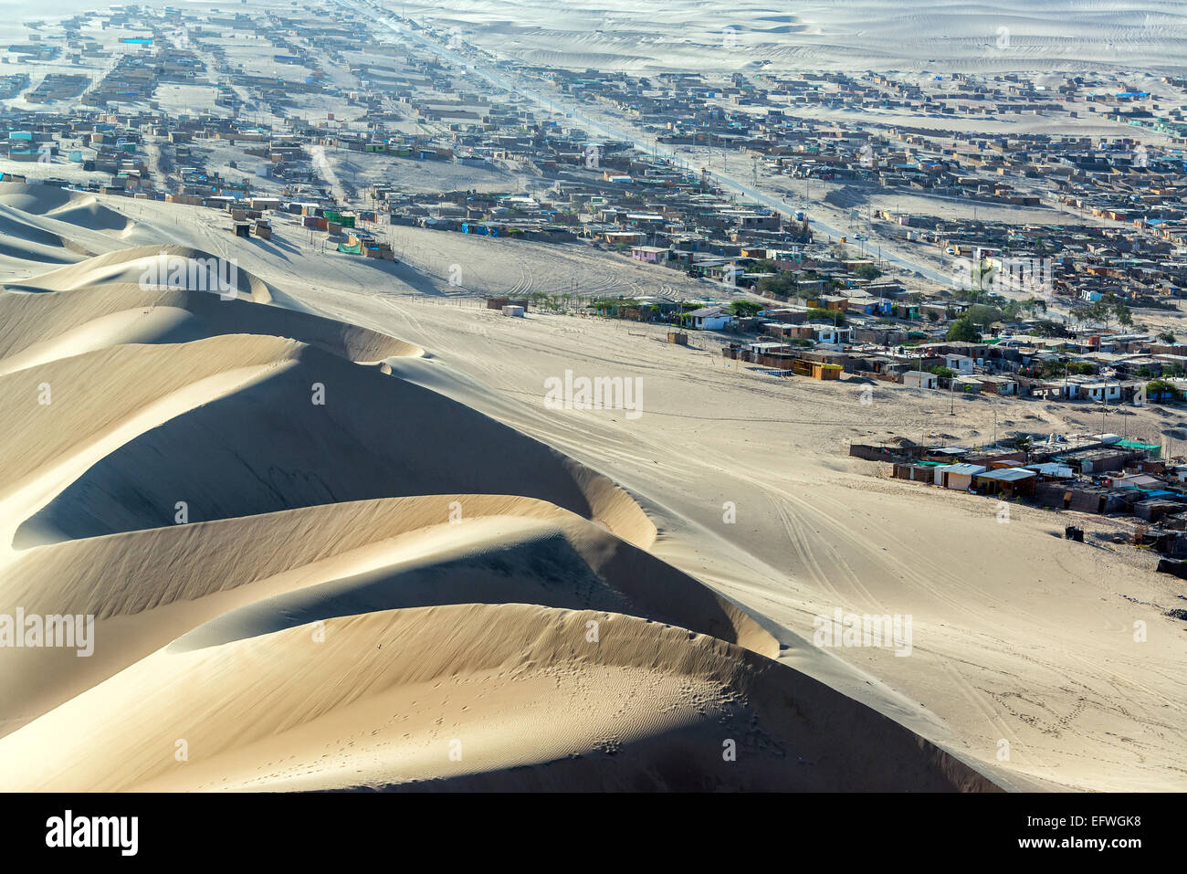 Row of sand dunes with a shantytown in the background at Huacachina ...