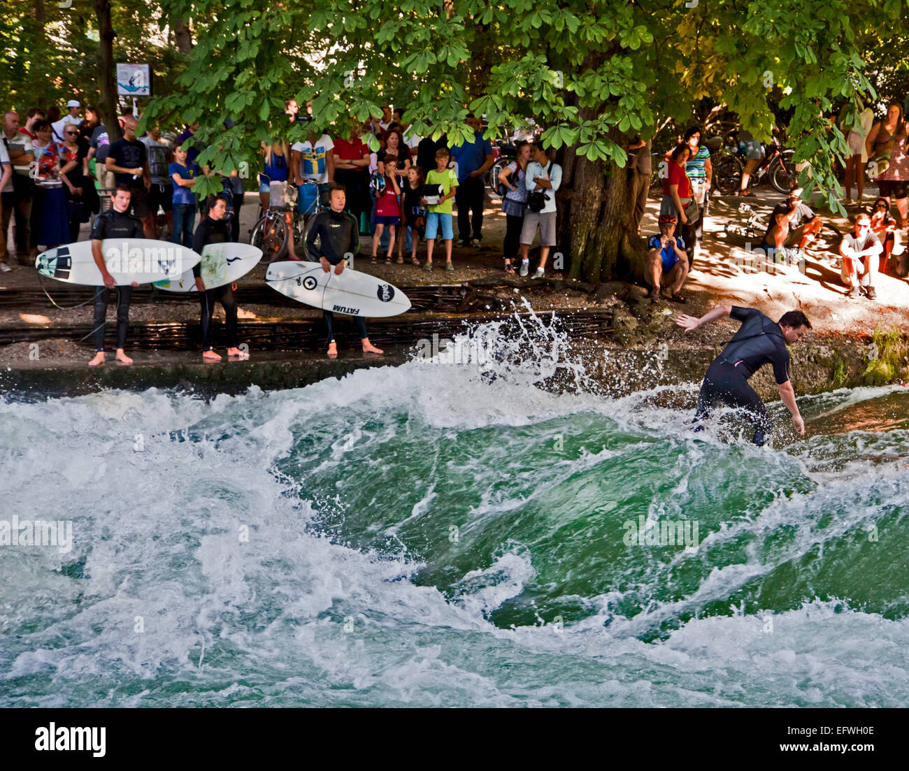 People enjoy a touristic attraction in Munich, surfers riding the ...