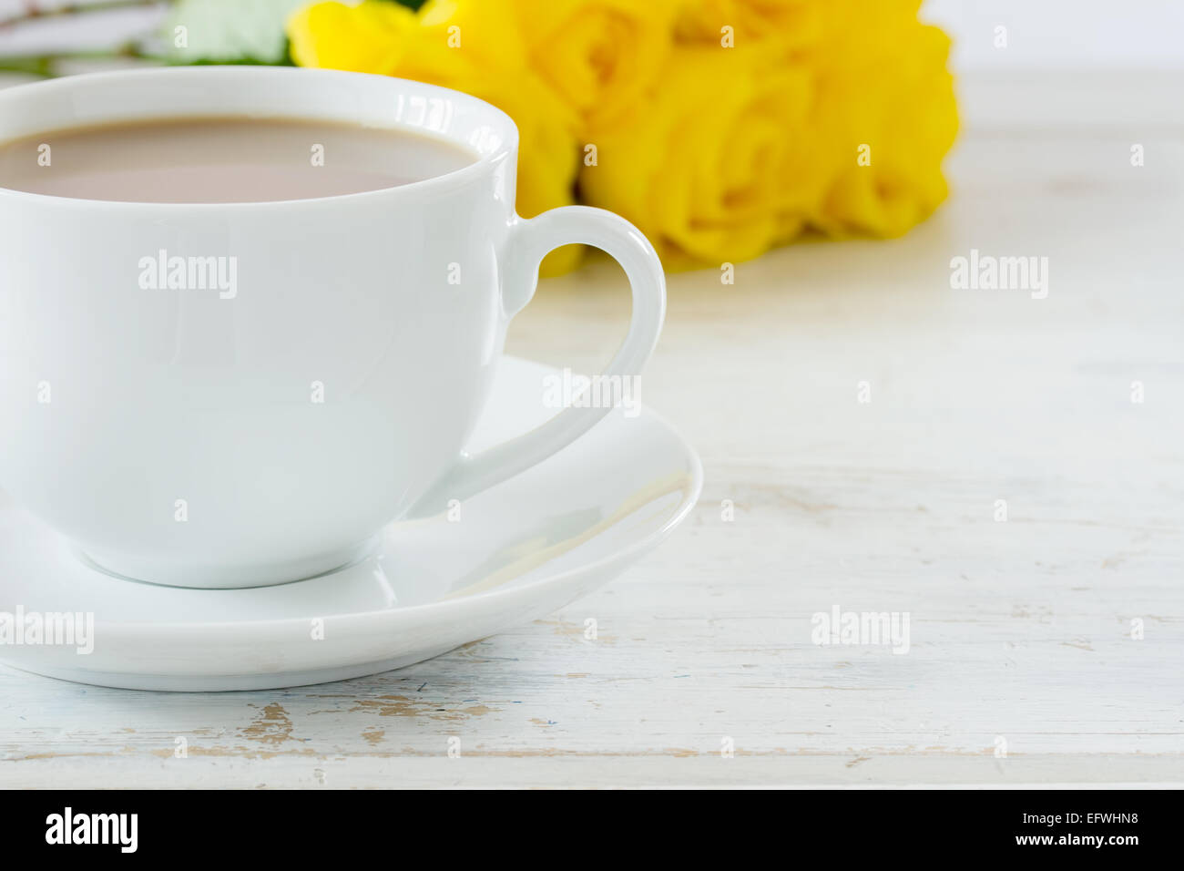 Cup of tea with a bouquet of yellow roses Stock Photo - Alamy