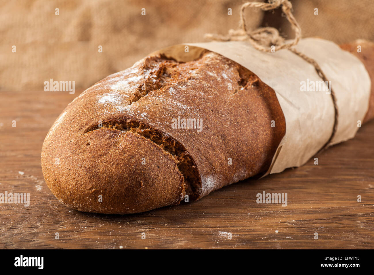 bread wrapped in paper on a wooden background Stock Photo - Alamy