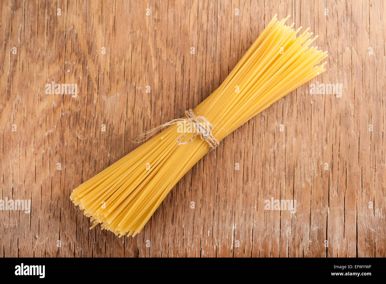 raw spaghetti tied with a rope on a wooden background Stock Photo - Alamy