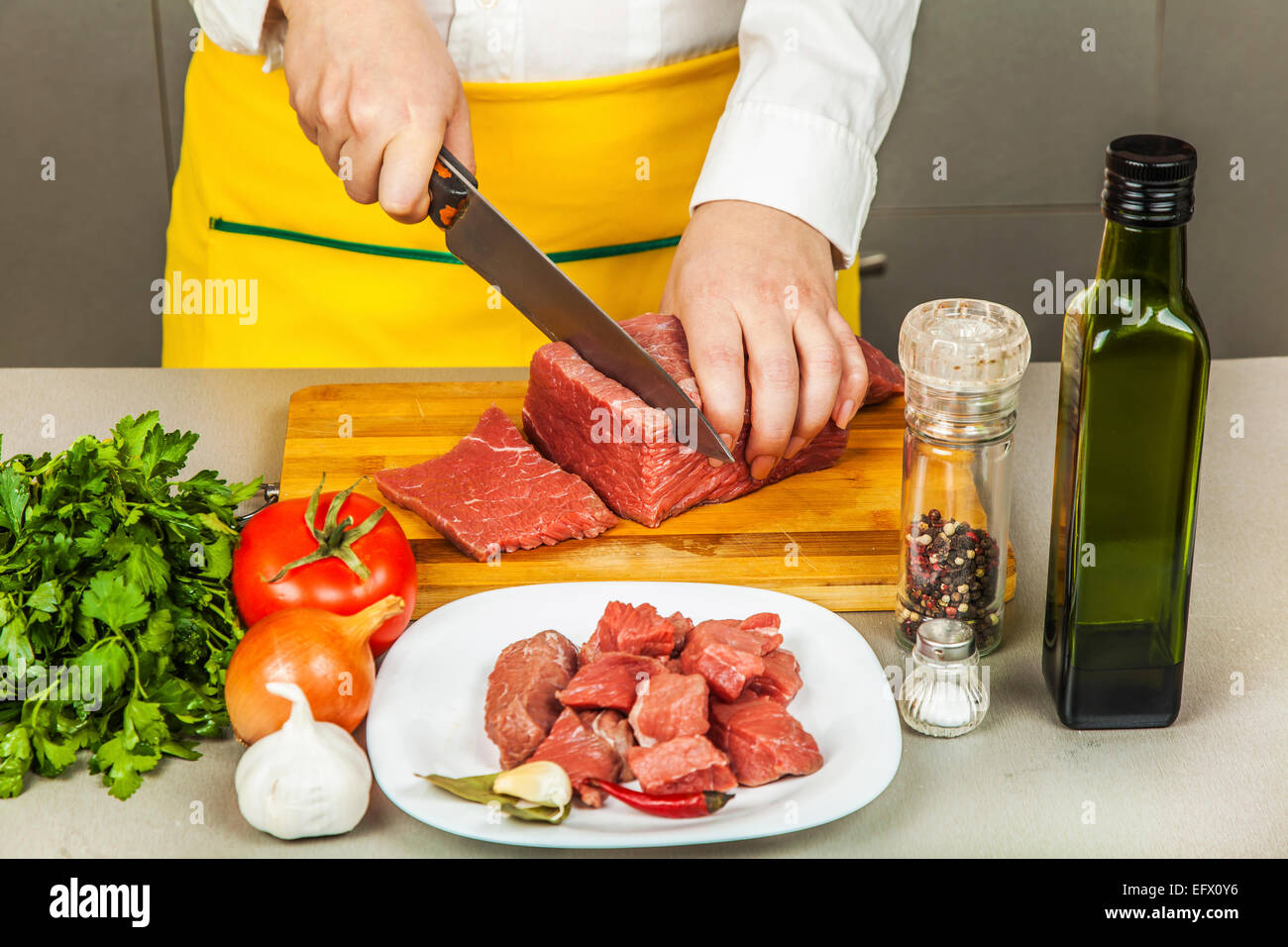 cook cuts meat fillet on a table with spices and vegetables Stock Photo ...