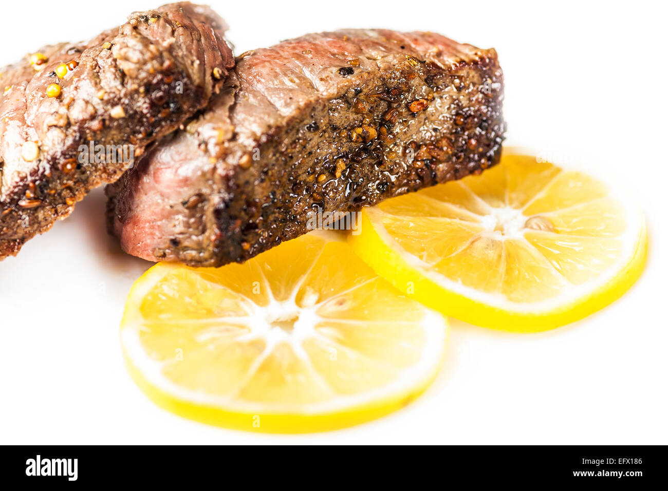 Sliced roasted meat with slices of lemon closeup on a light background ...