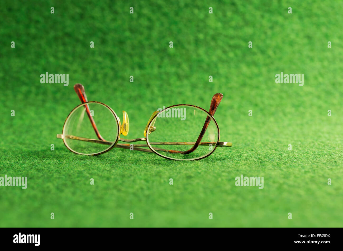old spectacles on green background Stock Photo - Alamy