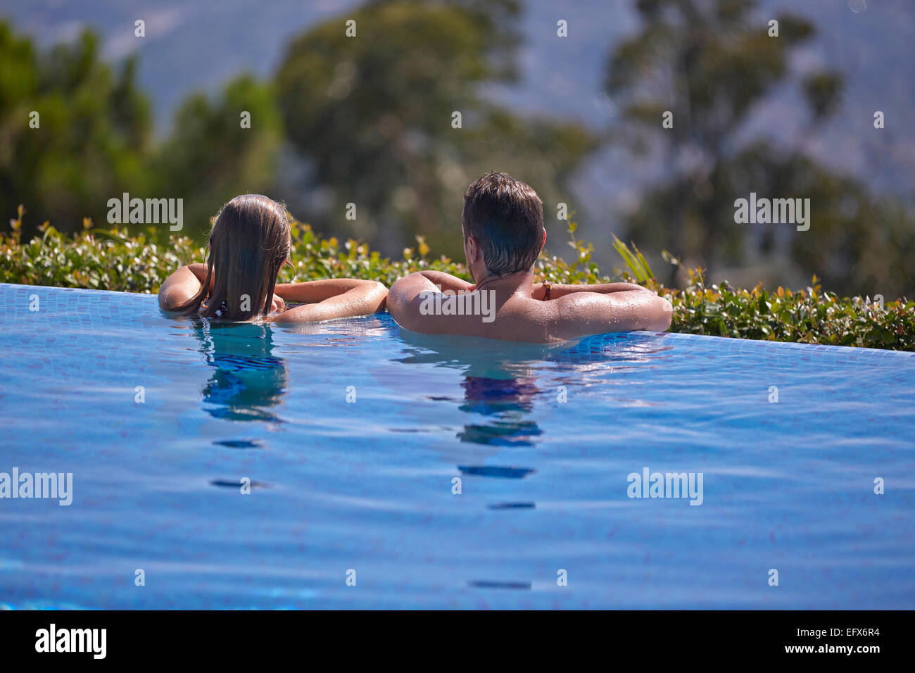 Couple on holiday in infinity pool in the South of France looking at ...