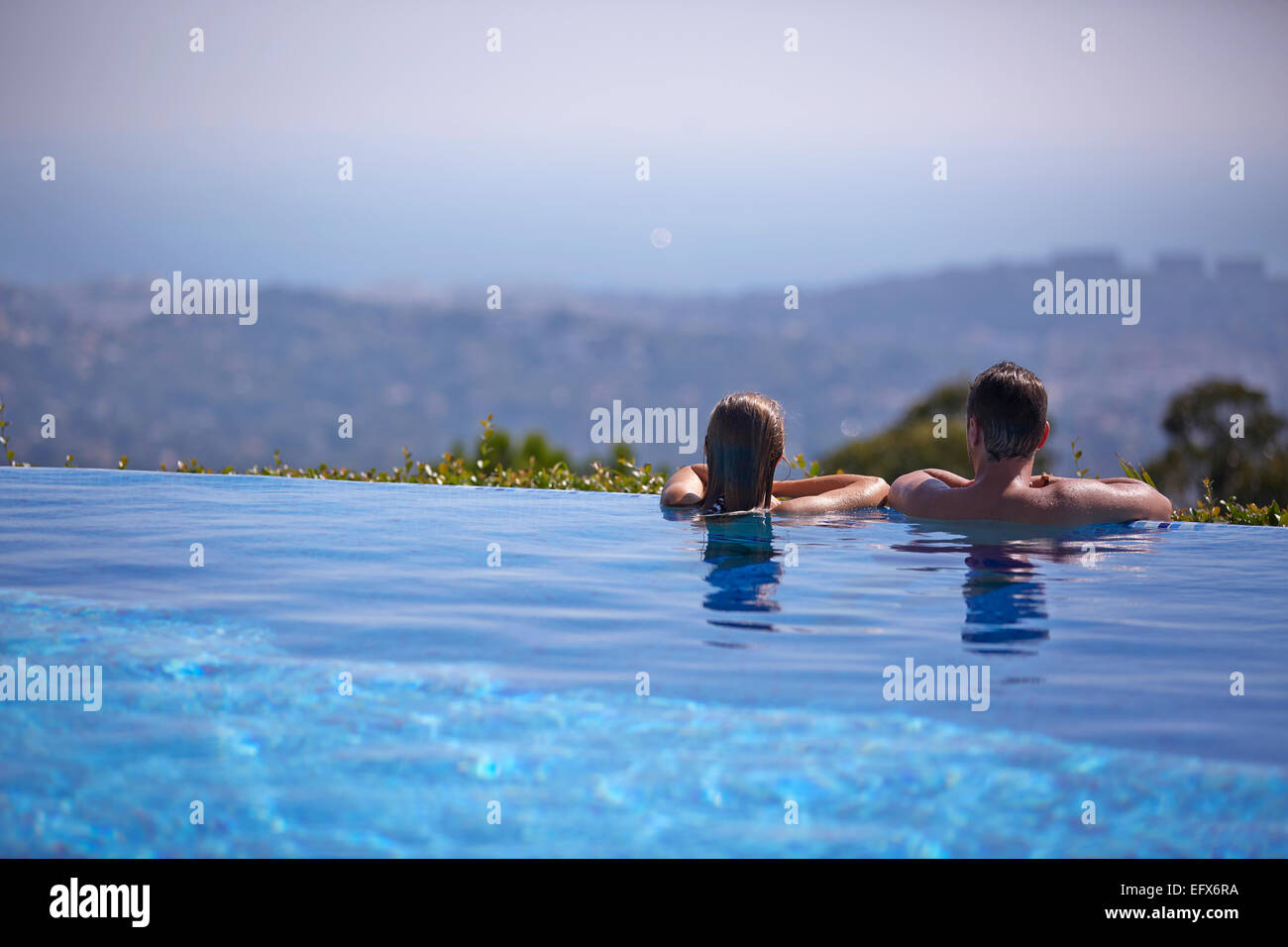 Couple on holiday in infinity pool in the South of France looking at ...