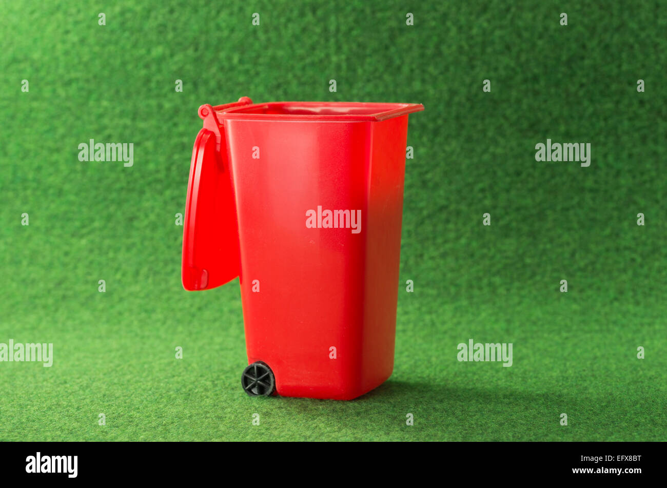 red open garbage bin container on green background Stock Photo - Alamy