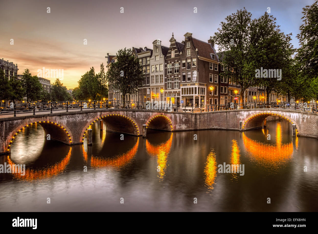 Illuminated arched bridges cast glowing reflections upon canals in ...