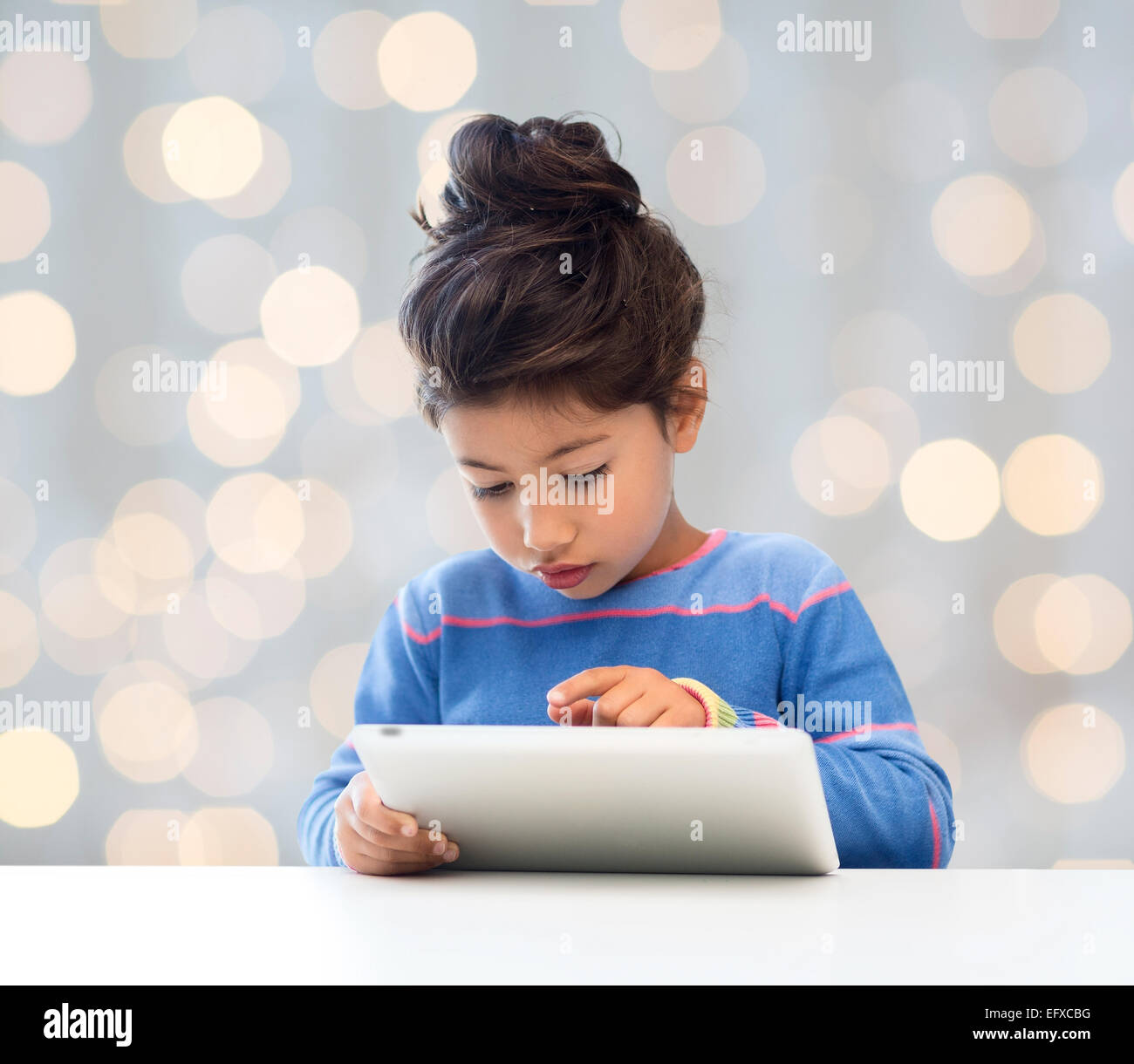 little girl with tablet pc over lights background Stock Photo - Alamy