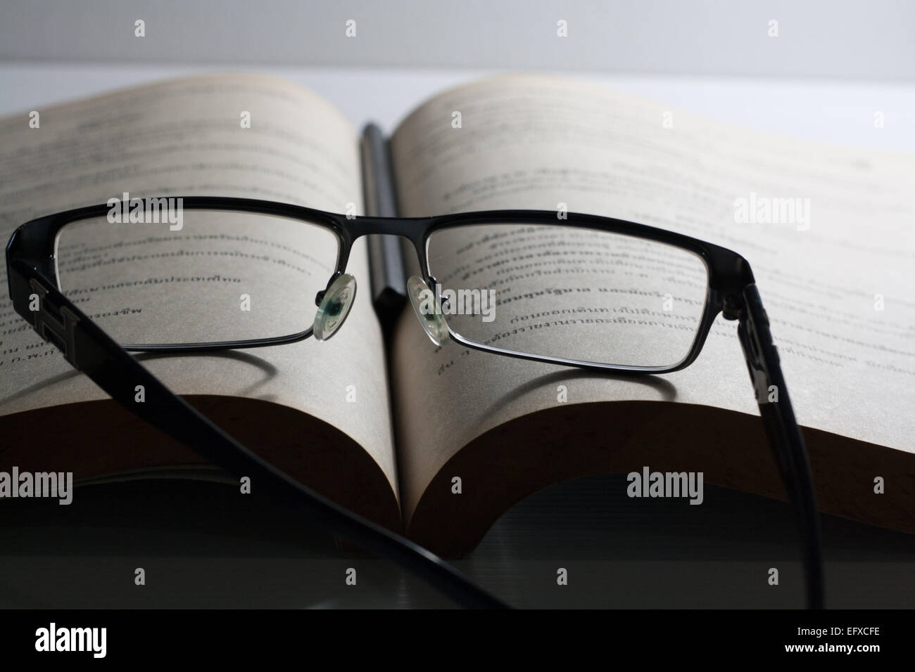 Open book and eyeglasses on desk Stock Photo - Alamy