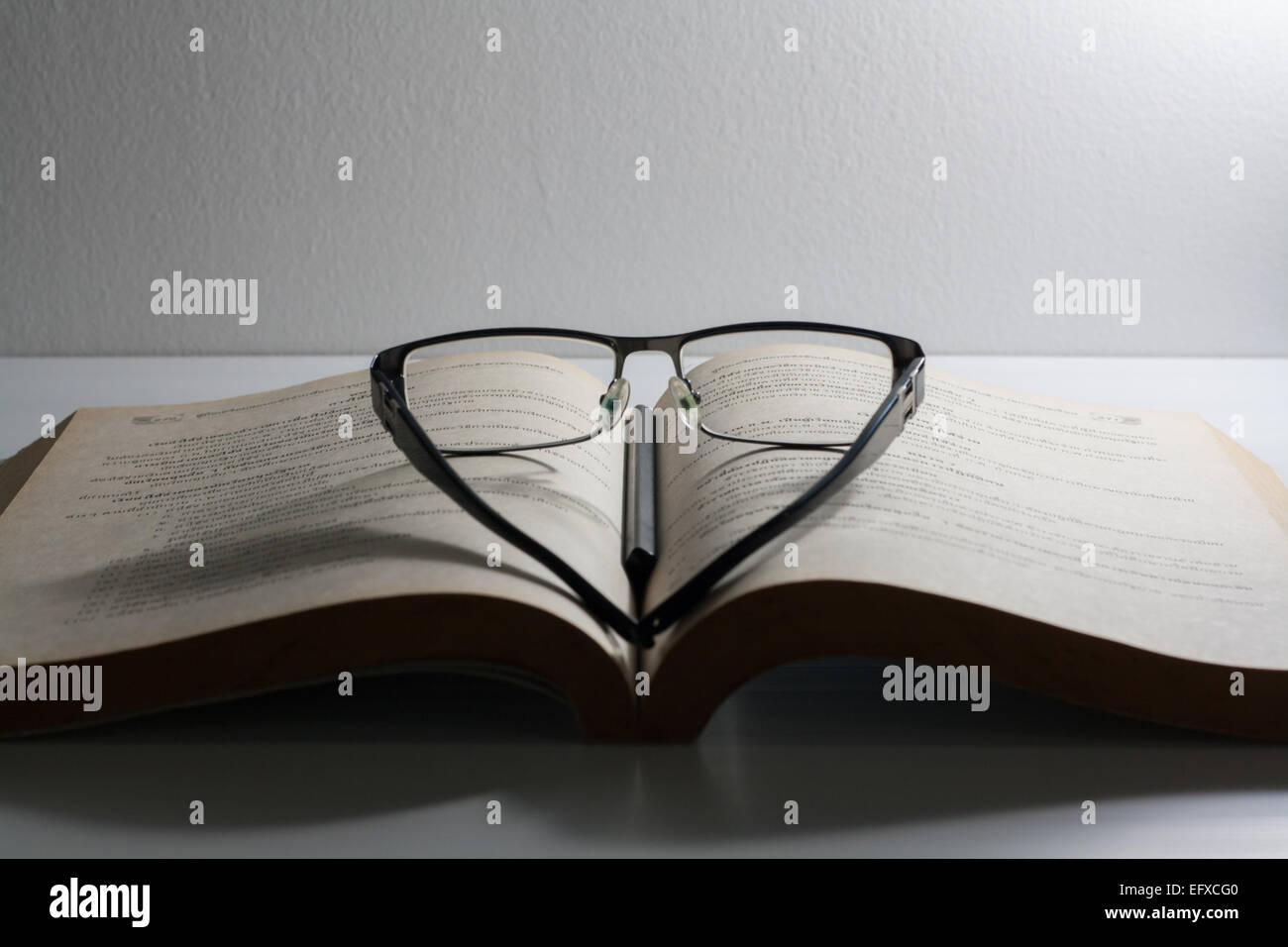 Open book and eyeglasses on desk Stock Photo - Alamy