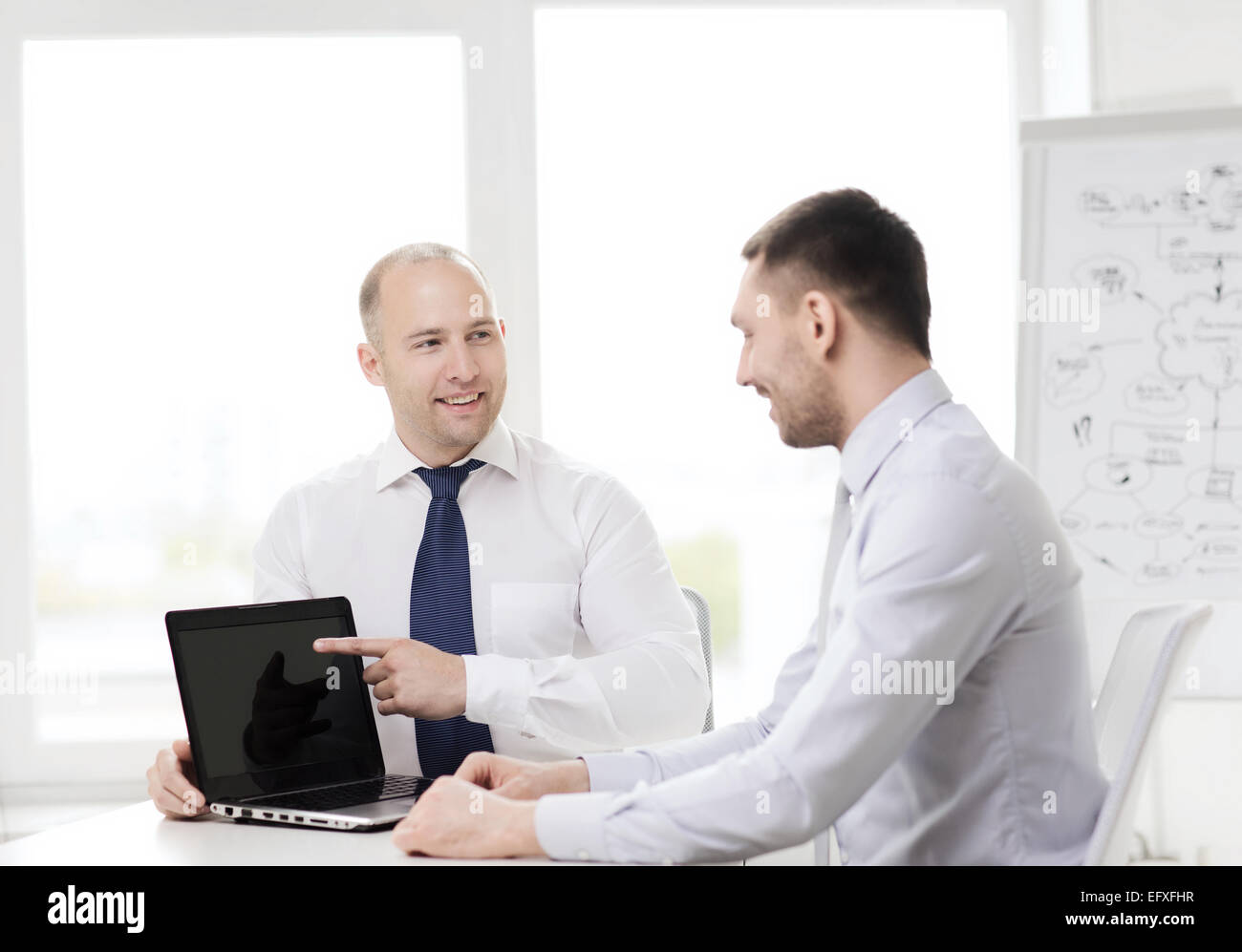 two smiling businessmen with laptop in office Stock Photo - Alamy