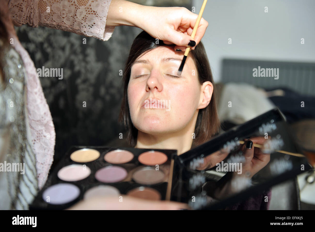 Makeup artist applies eyeshadow to a lady Stock Photo - Alamy