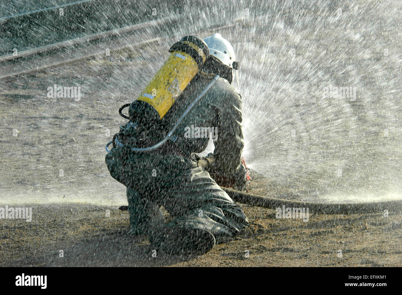 Firefighter in protective suit works with water cannon Stock Photo - Alamy