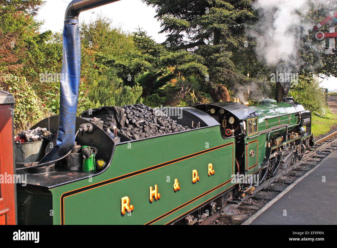 Narrow-gauge steam locomotive taking on water at New Romney Station ...