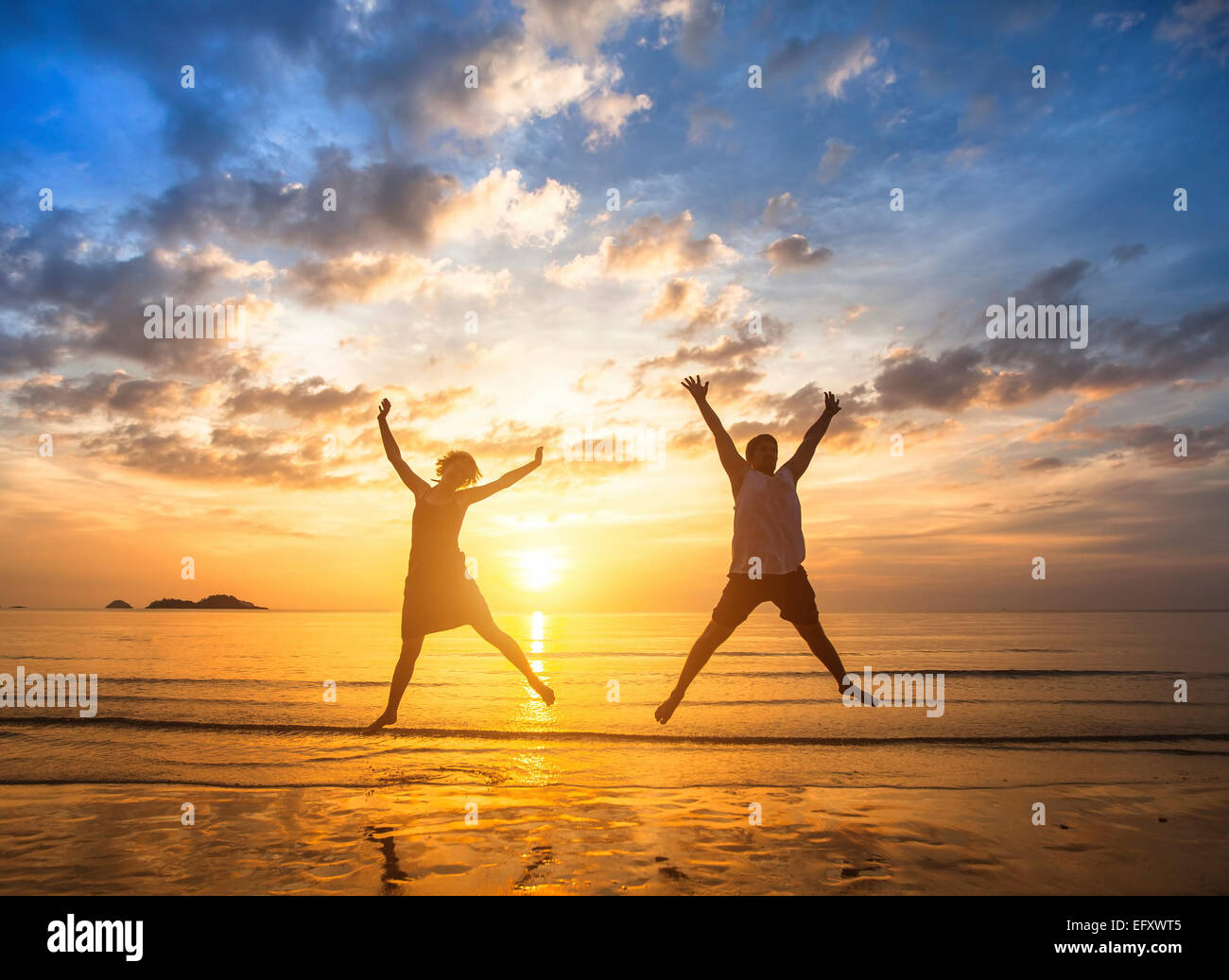 Couple in love to jump up on the beach during a stunning sunset Stock ...