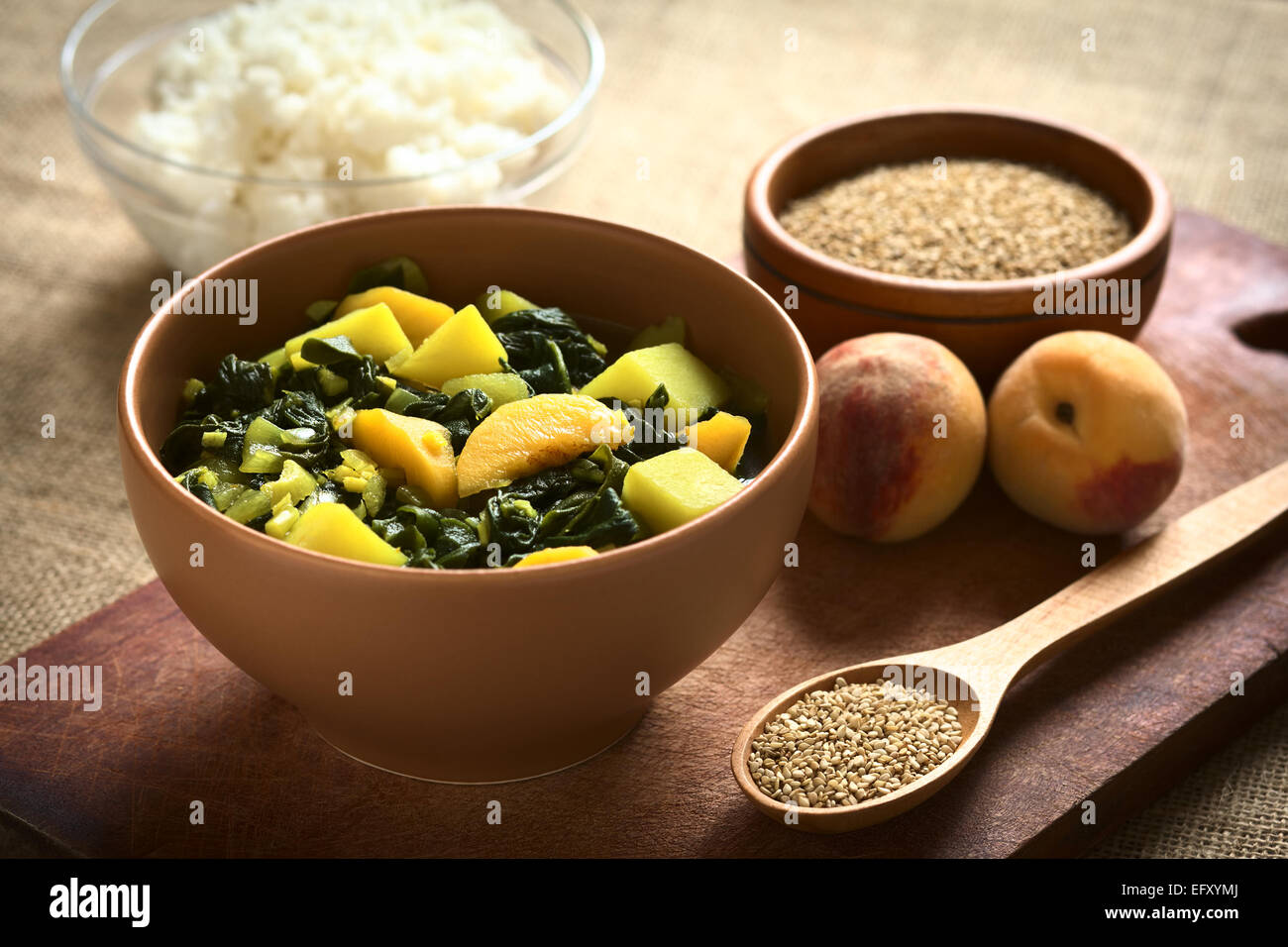 Bowl of spinach, peach and potato curry dish with sesame seeds and ...