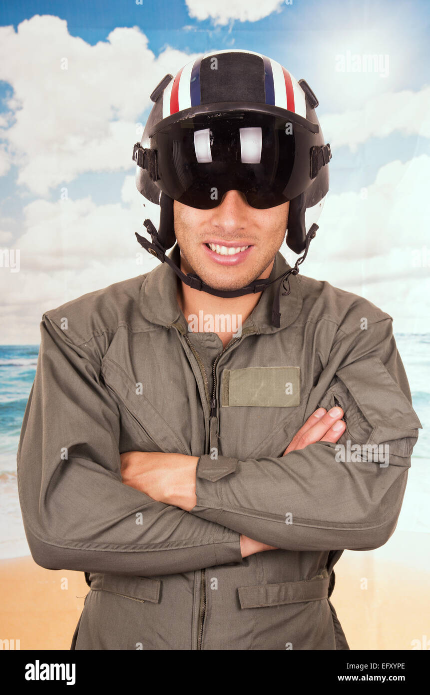 young handsome pilot wearing uniform and helmet over beach background ...
