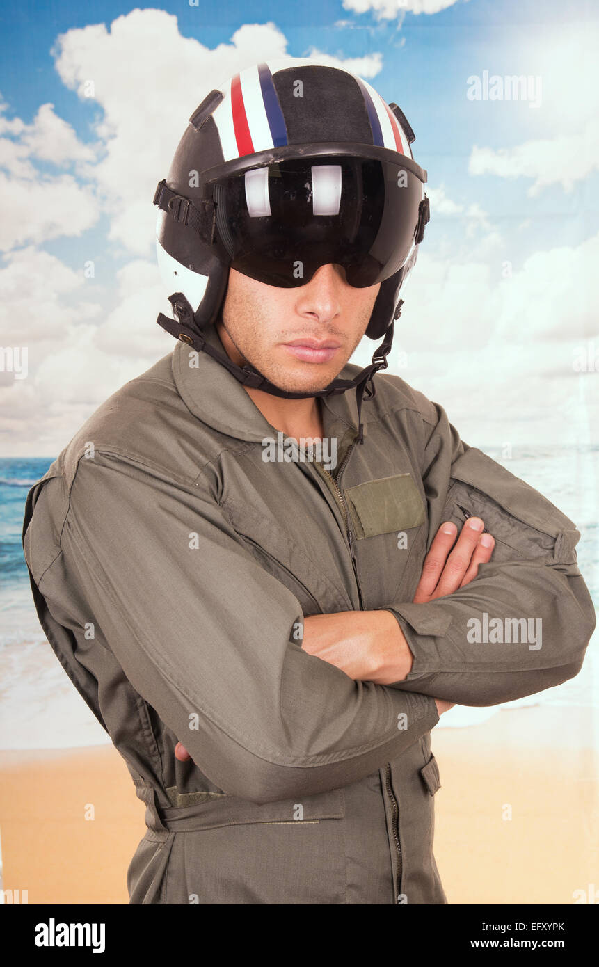 young handsome pilot wearing uniform and helmet over beach background ...