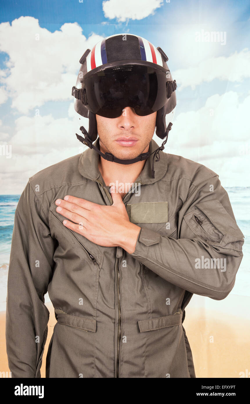 young handsome pilot wearing uniform and helmet over beach background ...