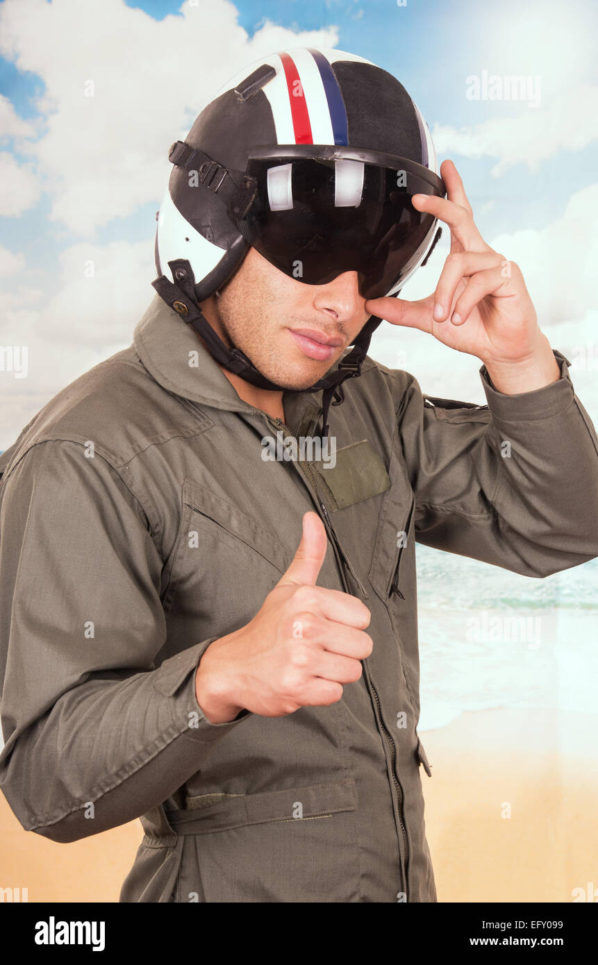 young handsome pilot wearing uniform and helmet over beach background ...