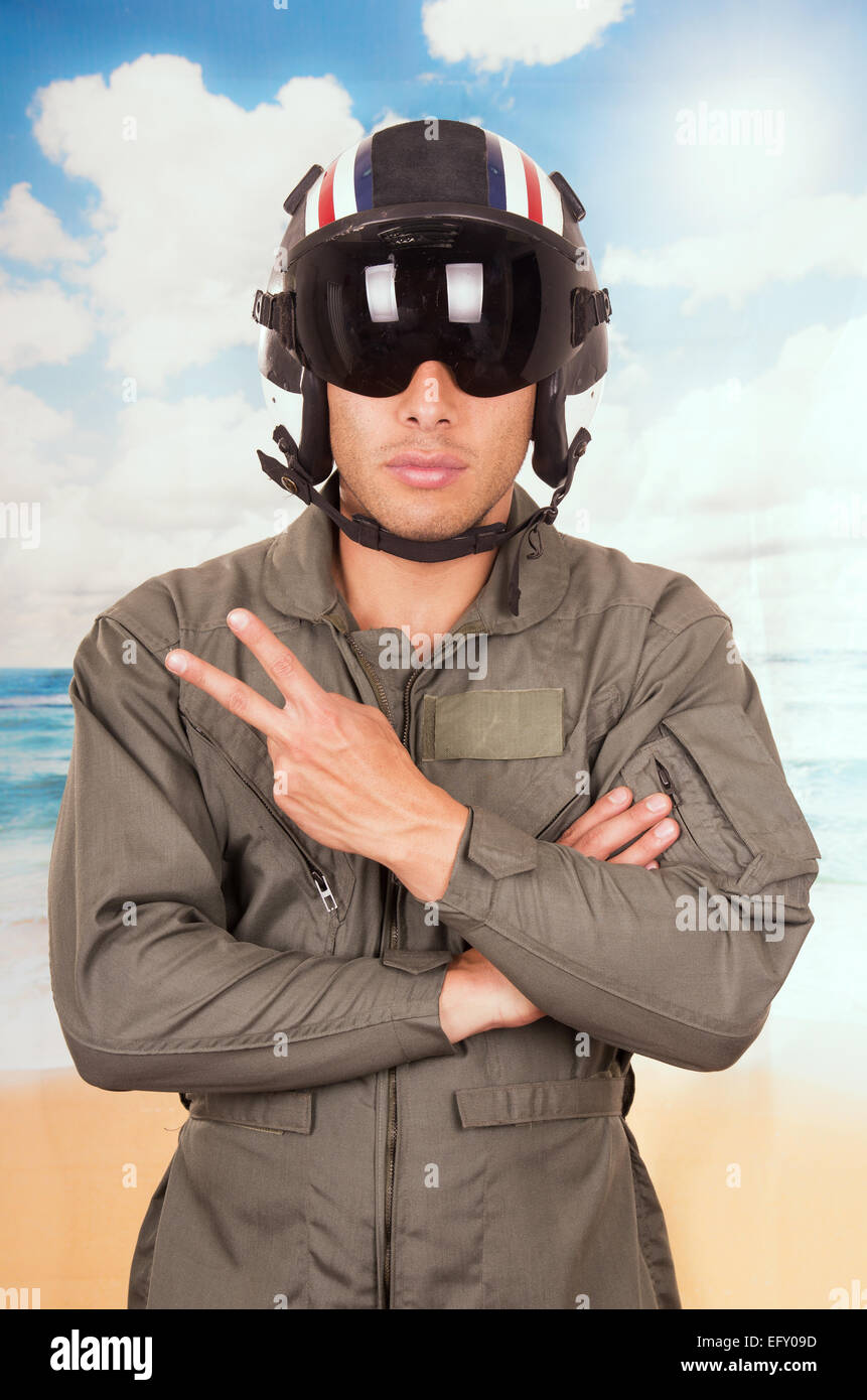 young handsome pilot wearing uniform and helmet over beach background ...