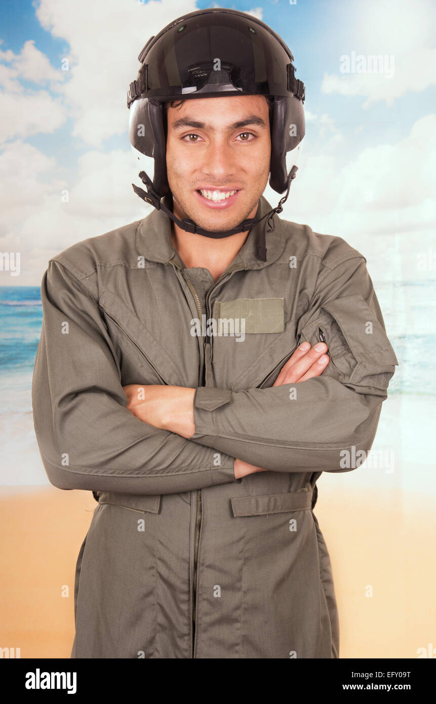 young handsome pilot wearing uniform and helmet over beach background ...