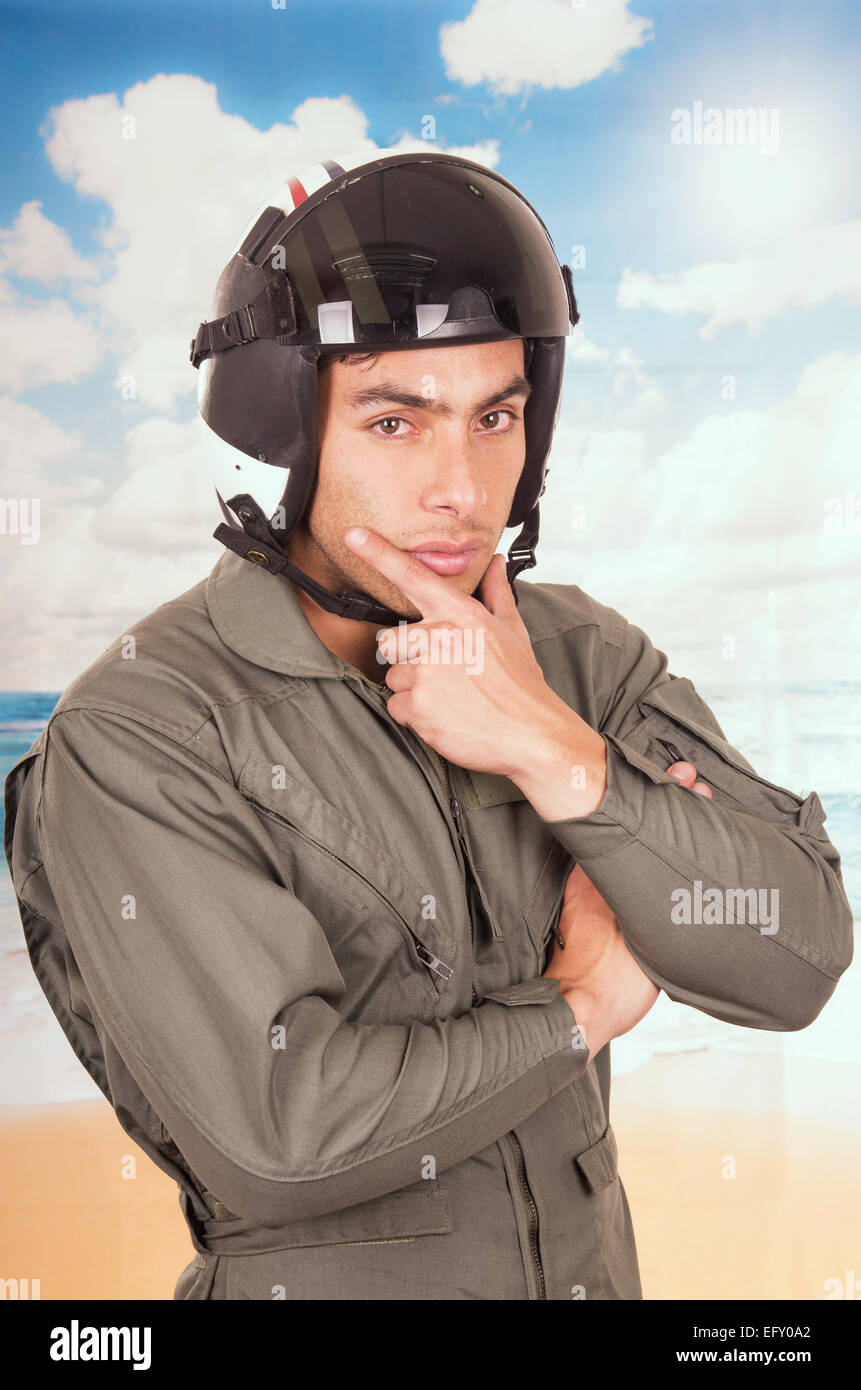young handsome pilot wearing uniform and helmet over beach background ...
