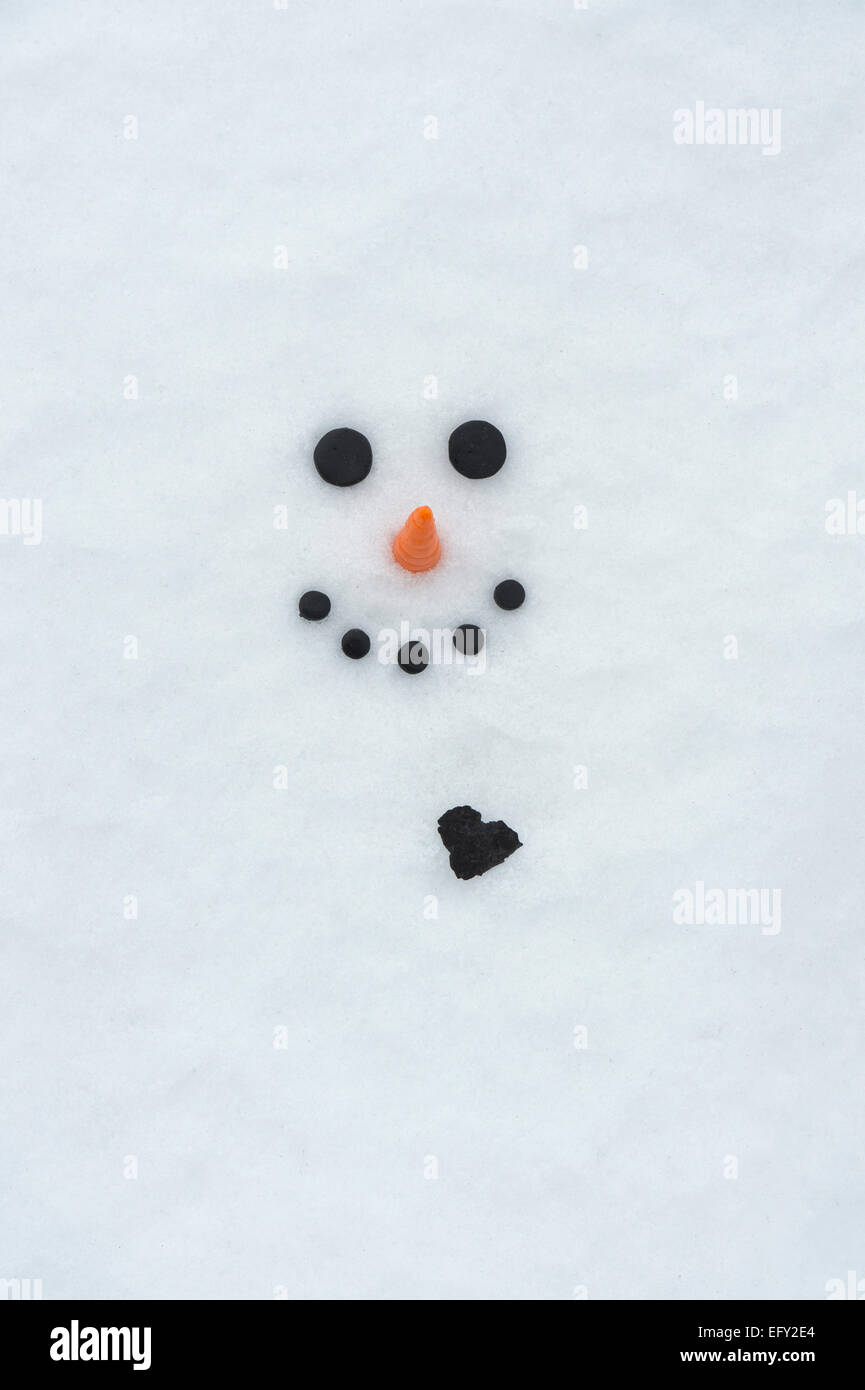 Happy snowman face with a big coal heart in the snow Stock Photo - Alamy
