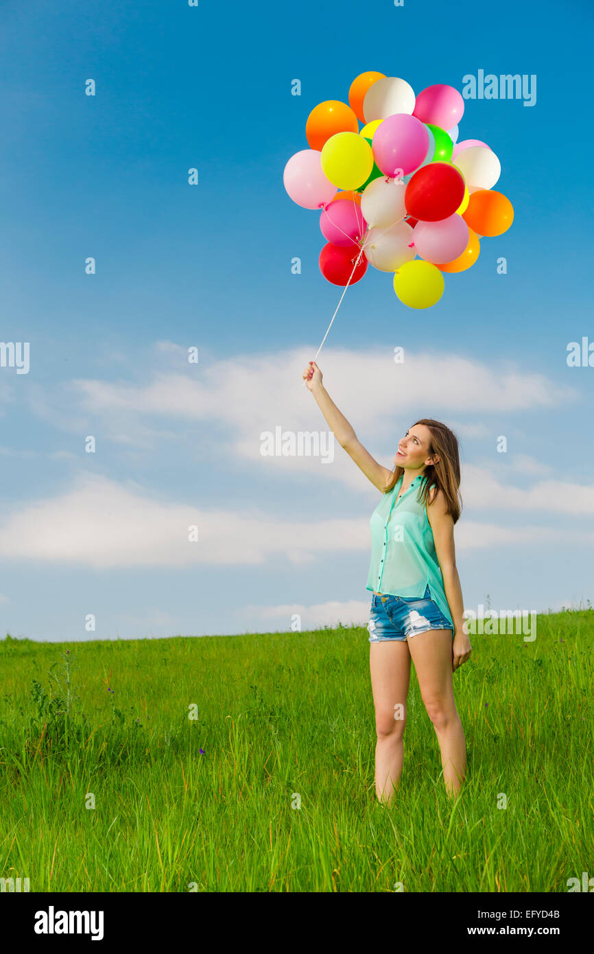 Young beautiful woman with colorful balloons on a green meadow Stock ...