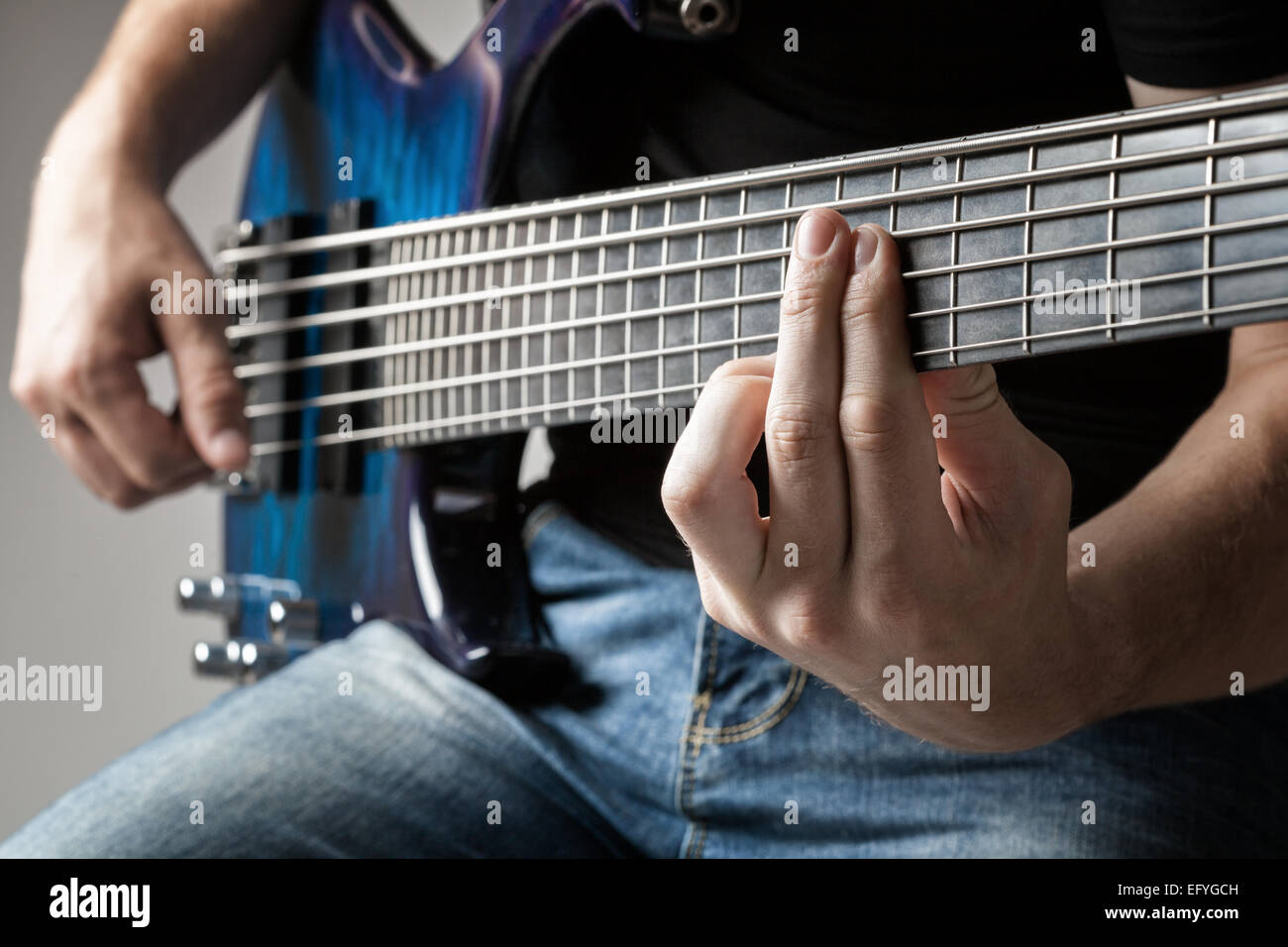 male musician playing on six-string bass guitar Stock Photo - Alamy