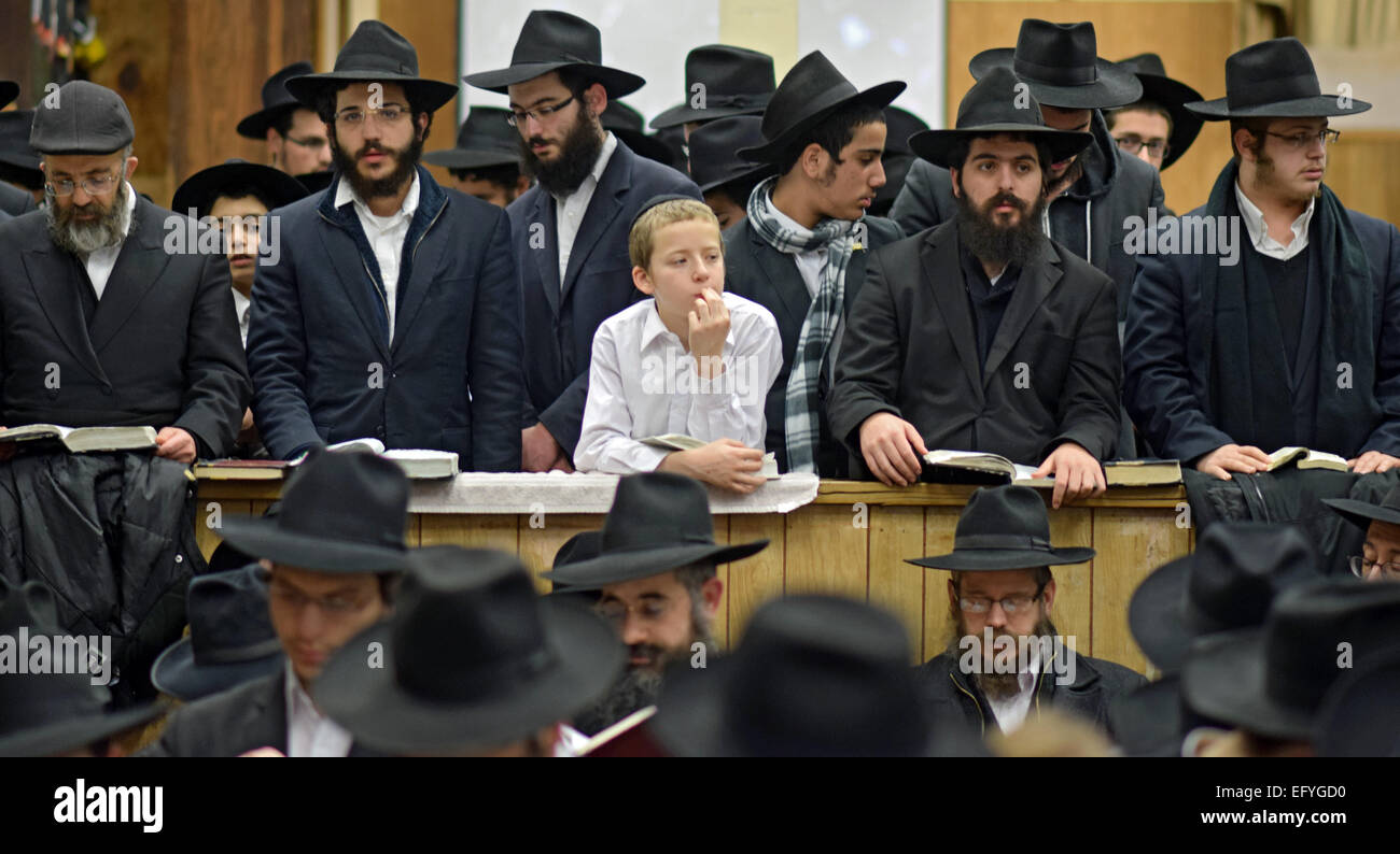 A young religious Jewish boy surrounded by older men at Chanukkah ...